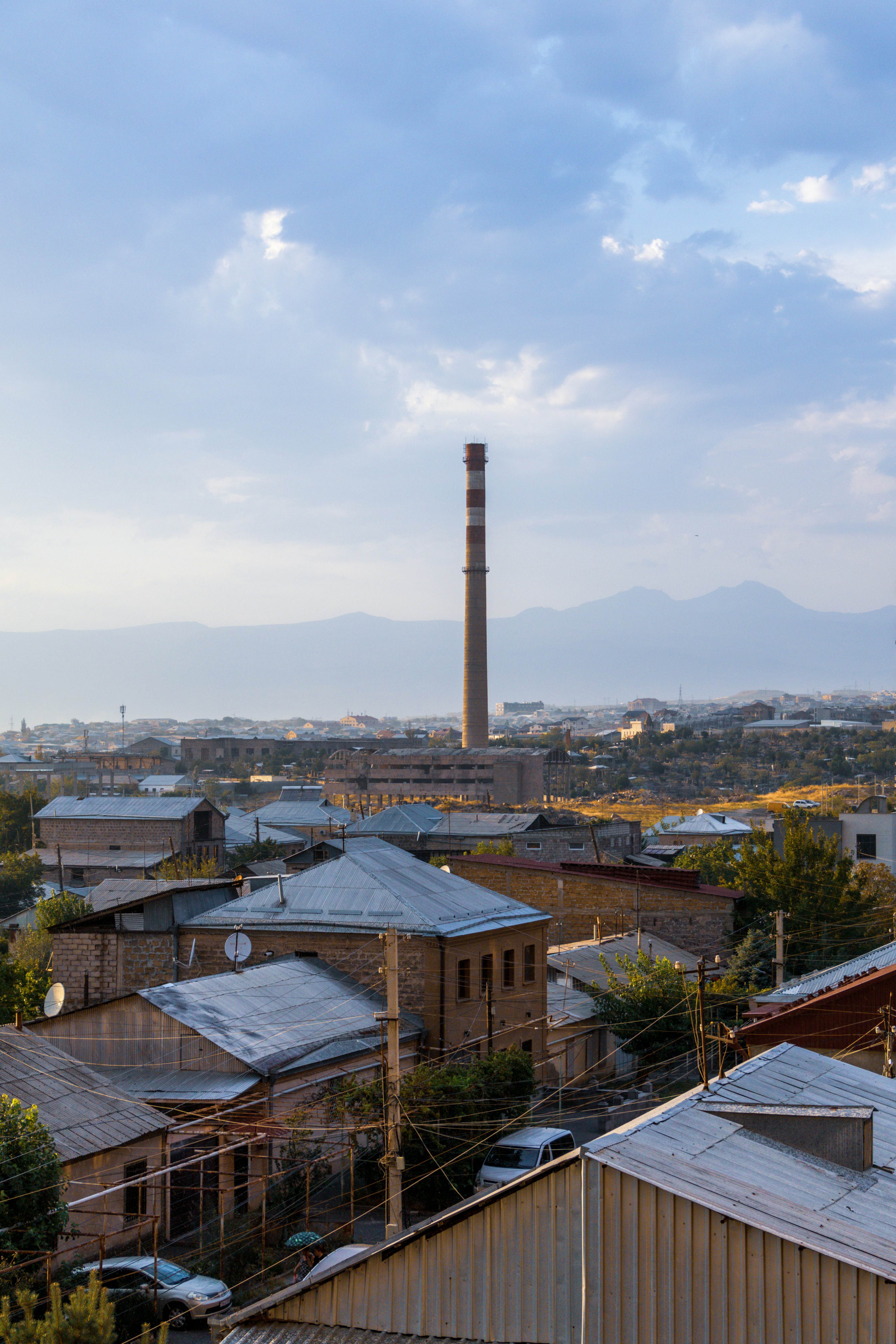 Chimney Pillar Rising Over a Corrugated Cityscape at Dusk