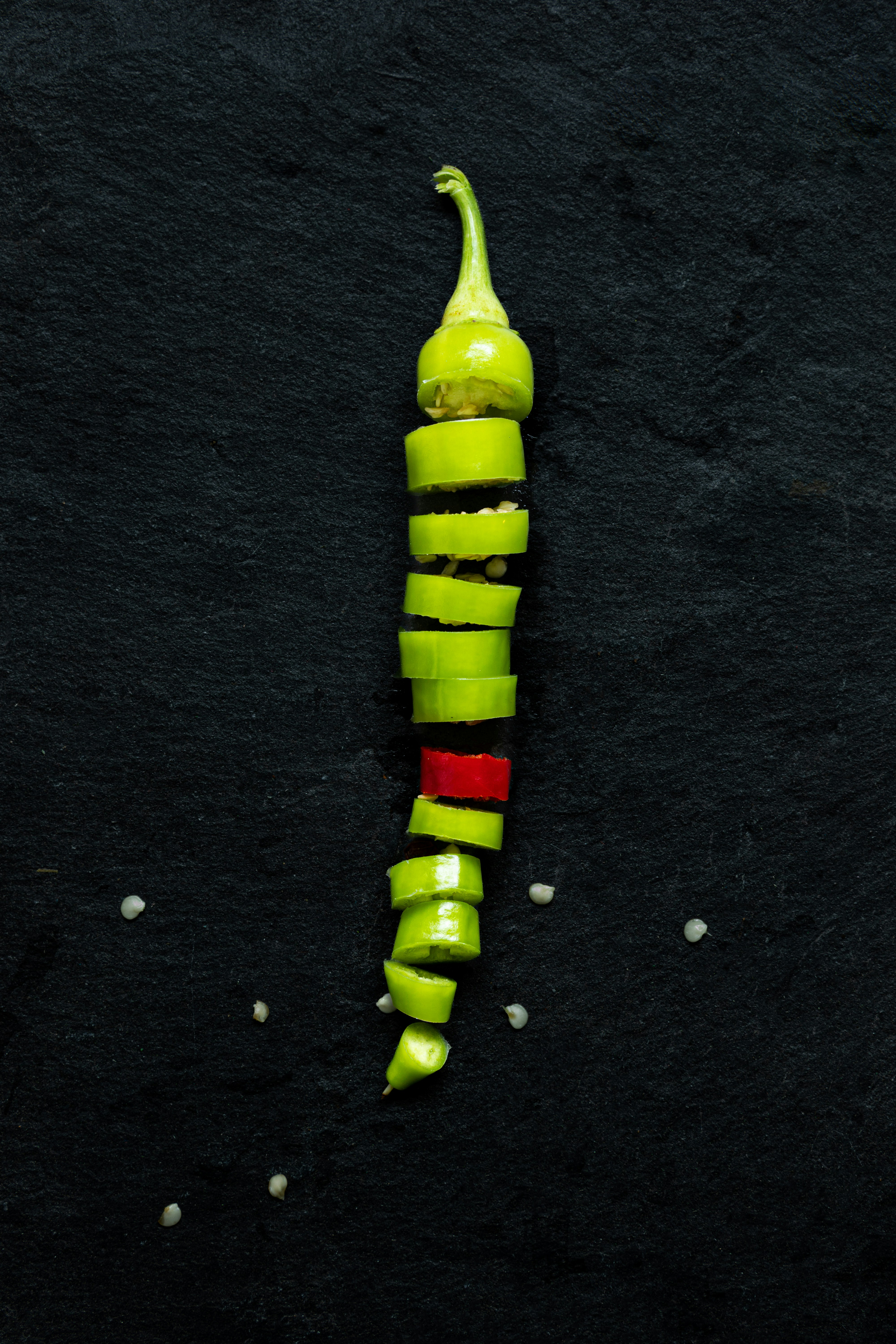 A green and red pepper sitting on top of a black surface photo – Free ...
