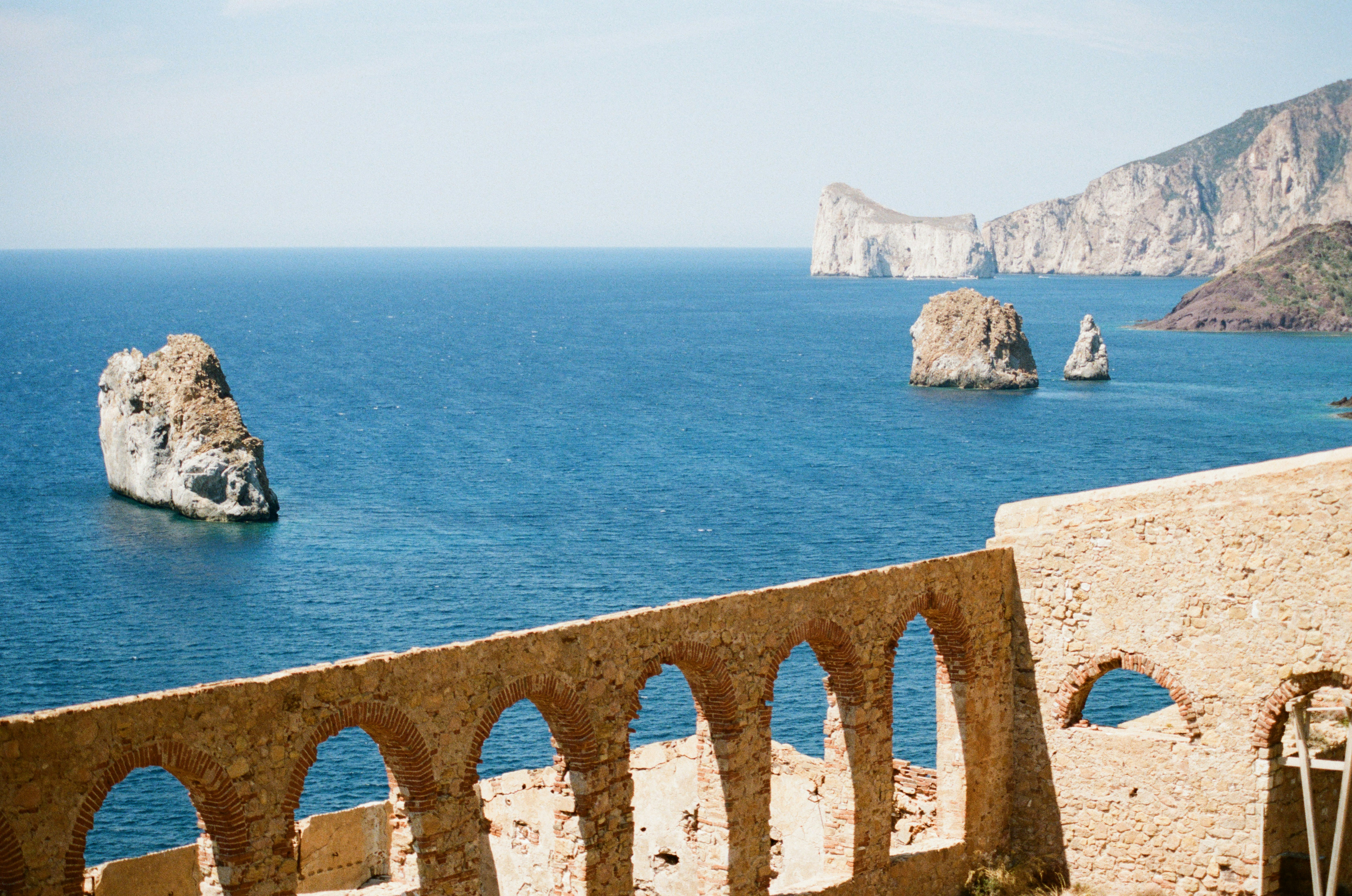 Stone Archway Framing a Calm Blue Sea, with Cliffed Horizons