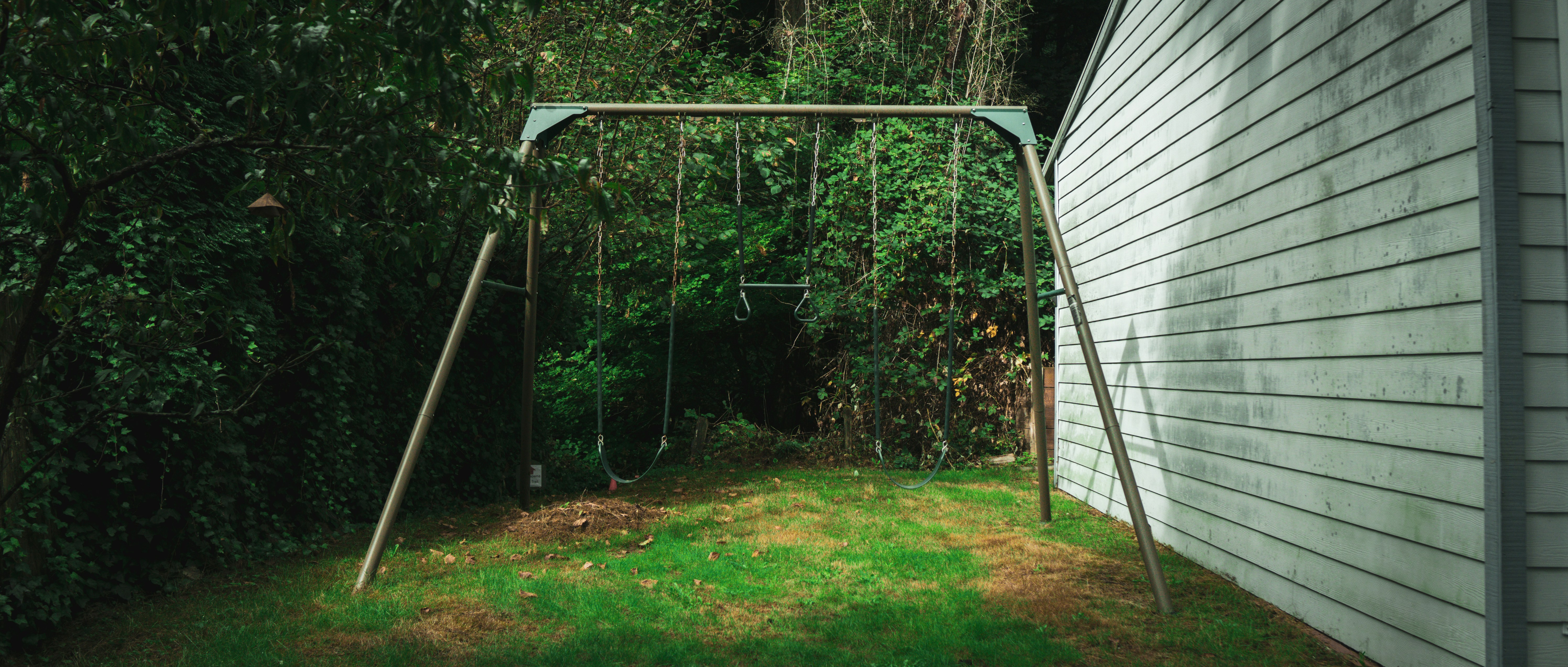 A swing set in a yard next to a house