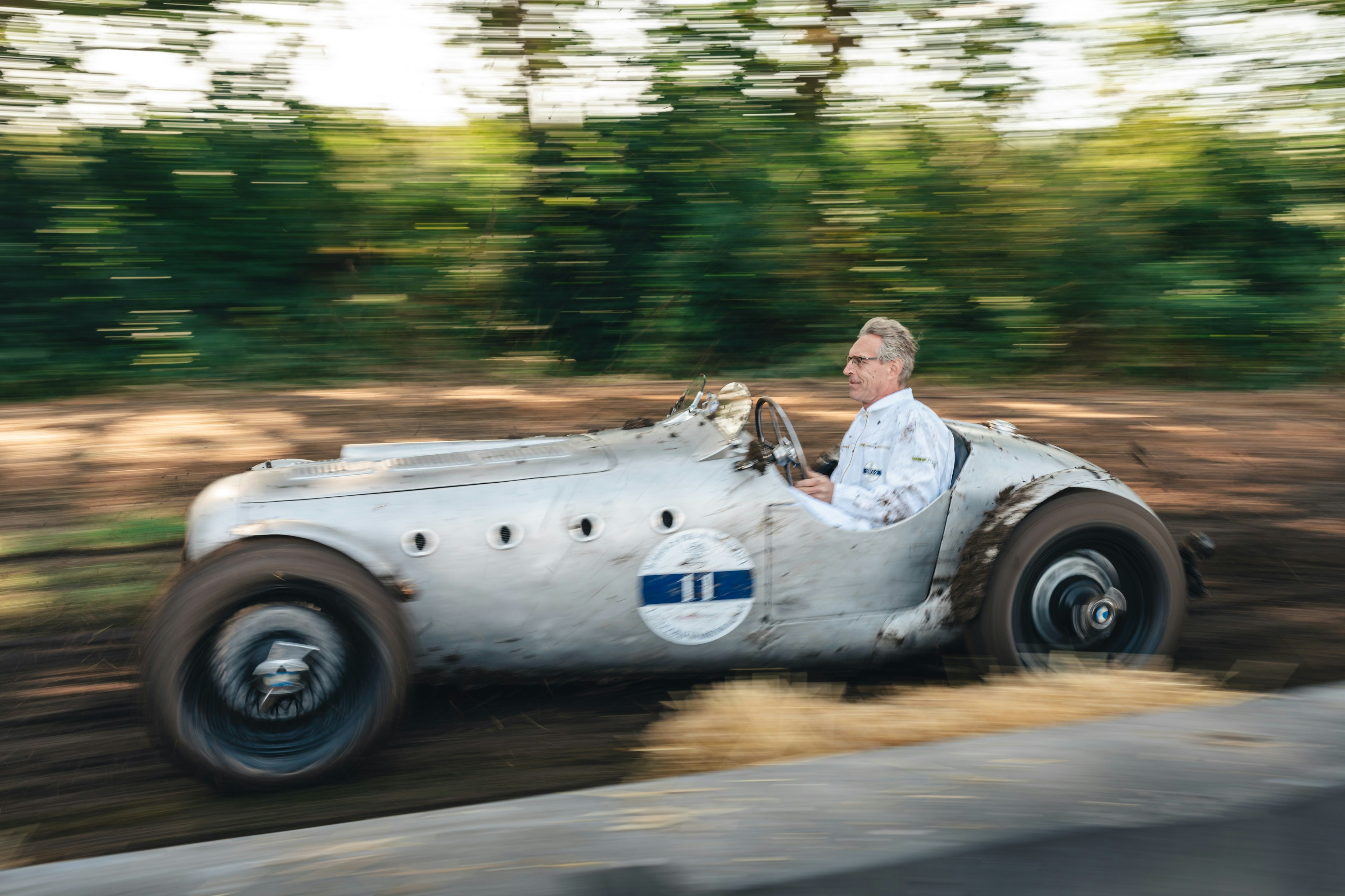 A man driving a silver race car down a road photo – Free Car Image on ...