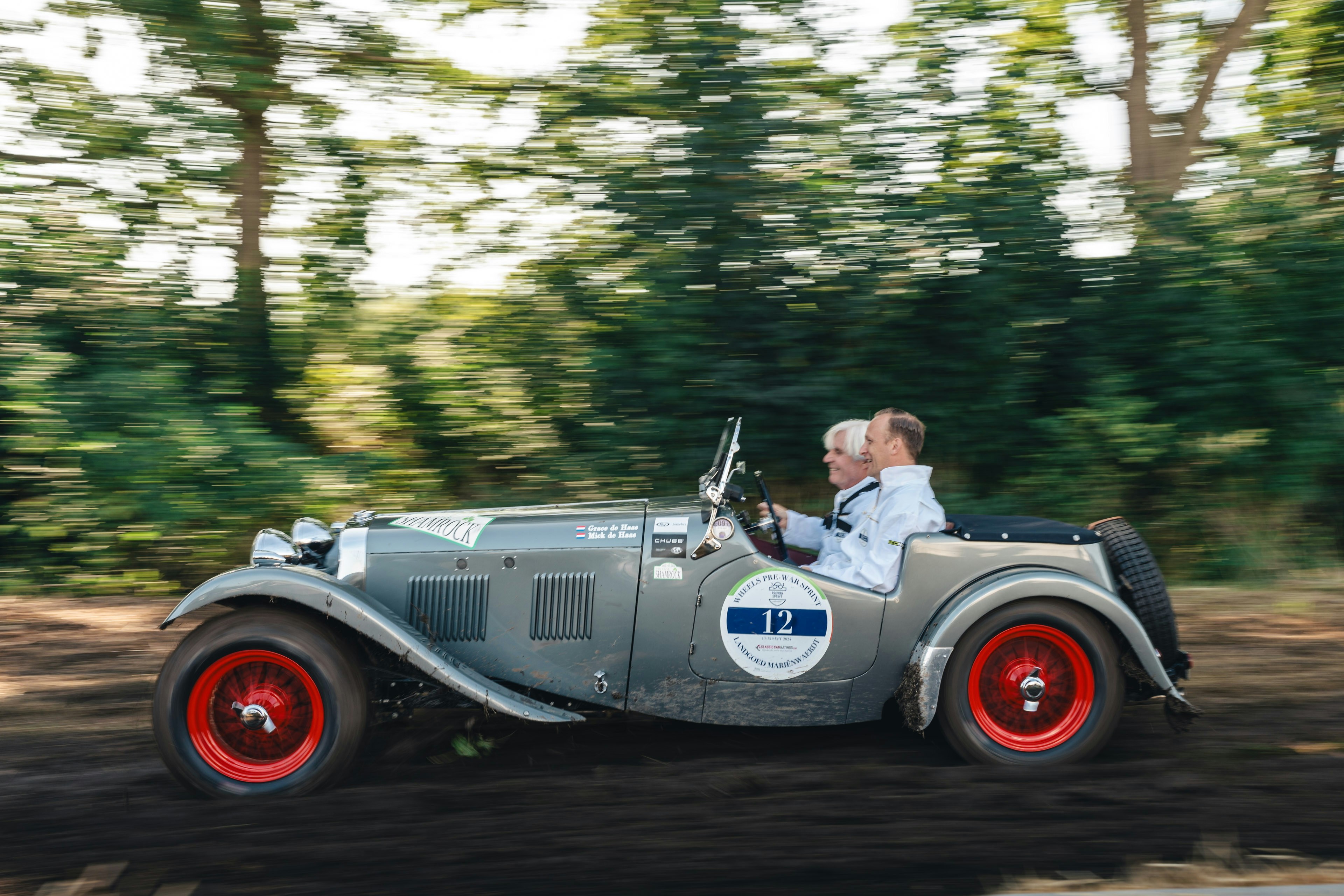 Vintage Convertible in Motion: A Pair of Drivers in an Open Road Parade
