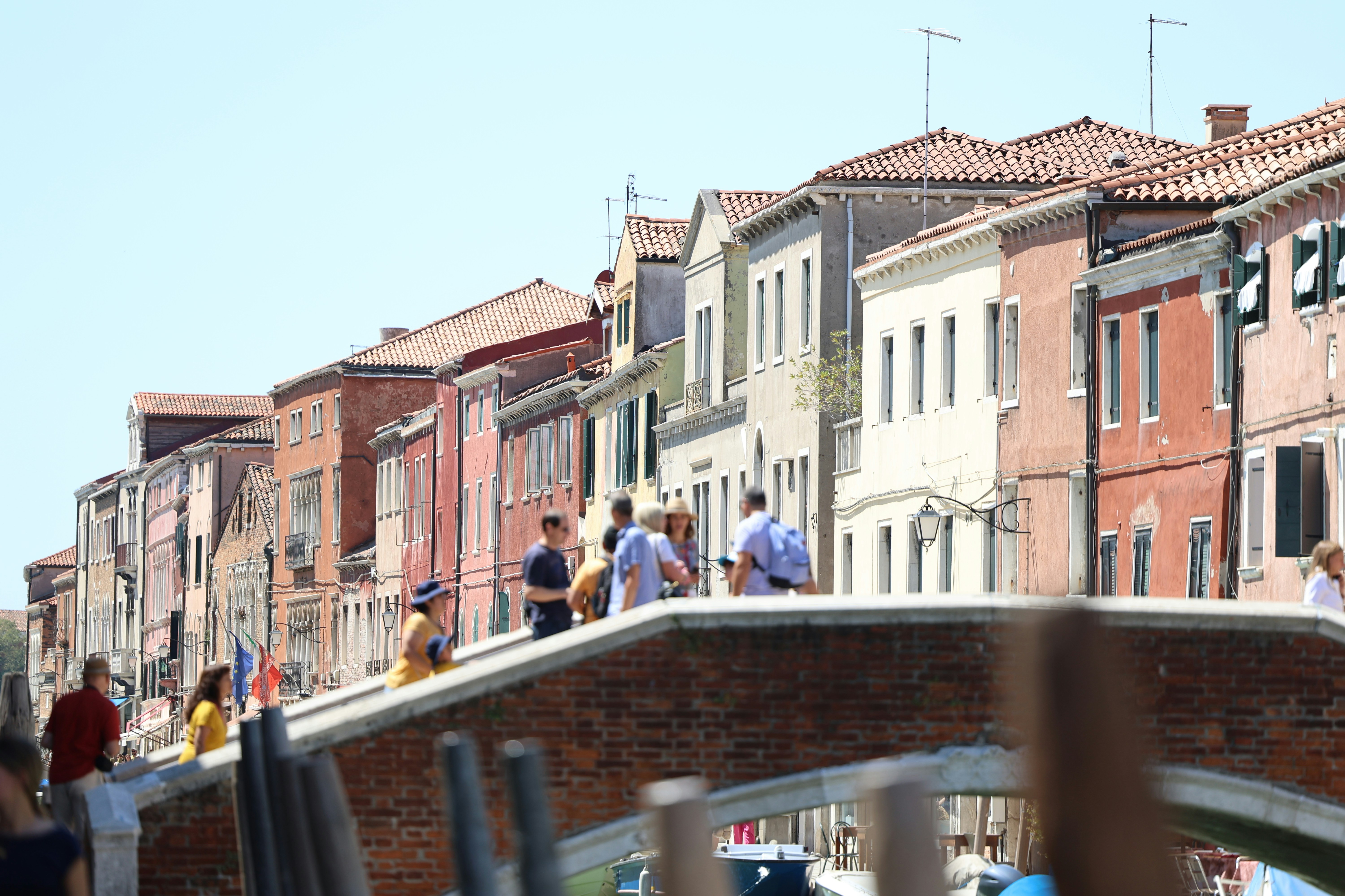 Color Over the Canal: Pedestrians Crossing a Brick-Arched Bridge Amid Bright Facades