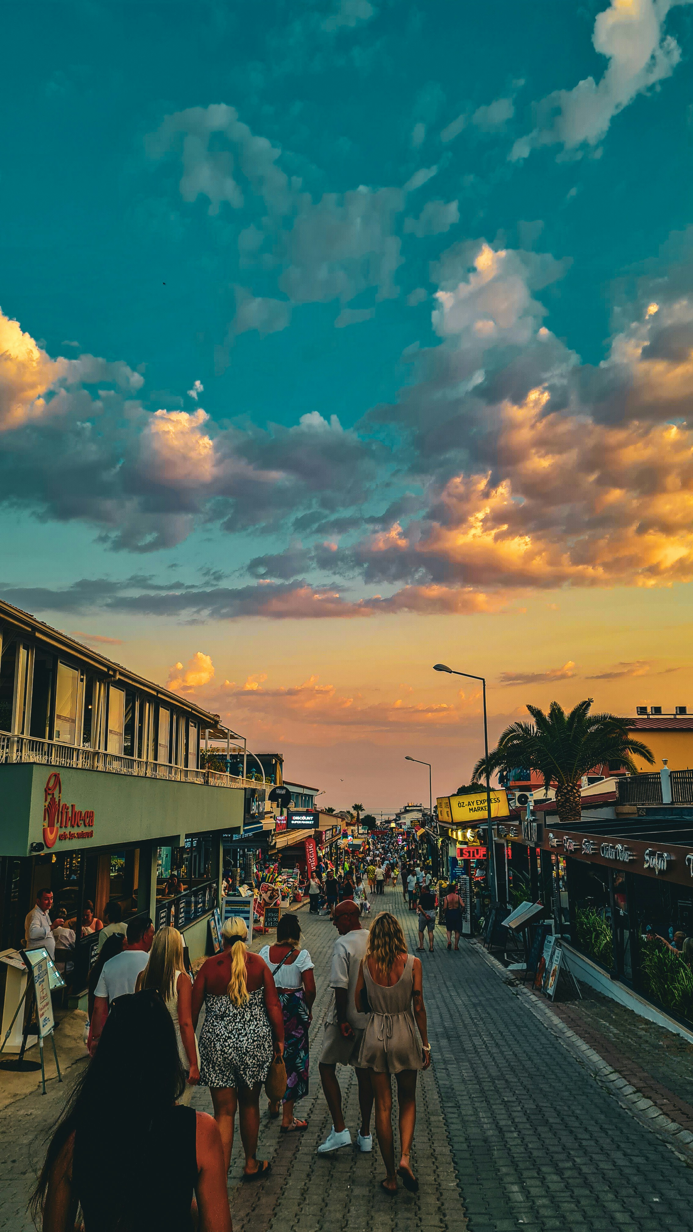 Sunset Promenade: A Crowded Coastal Street Bordered by Shops and Palms