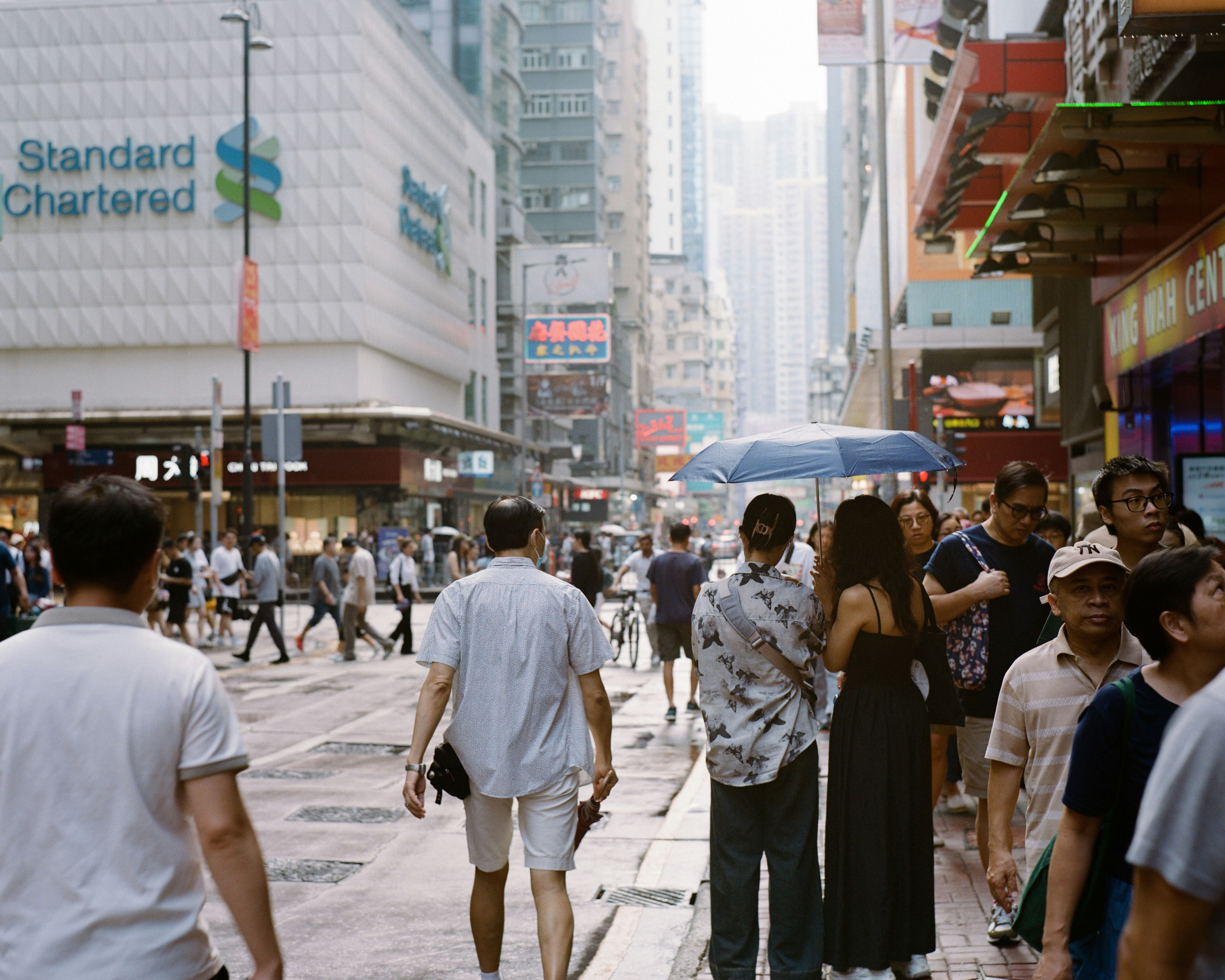 A crowd of people walking down a street next to tall buildings photo ...