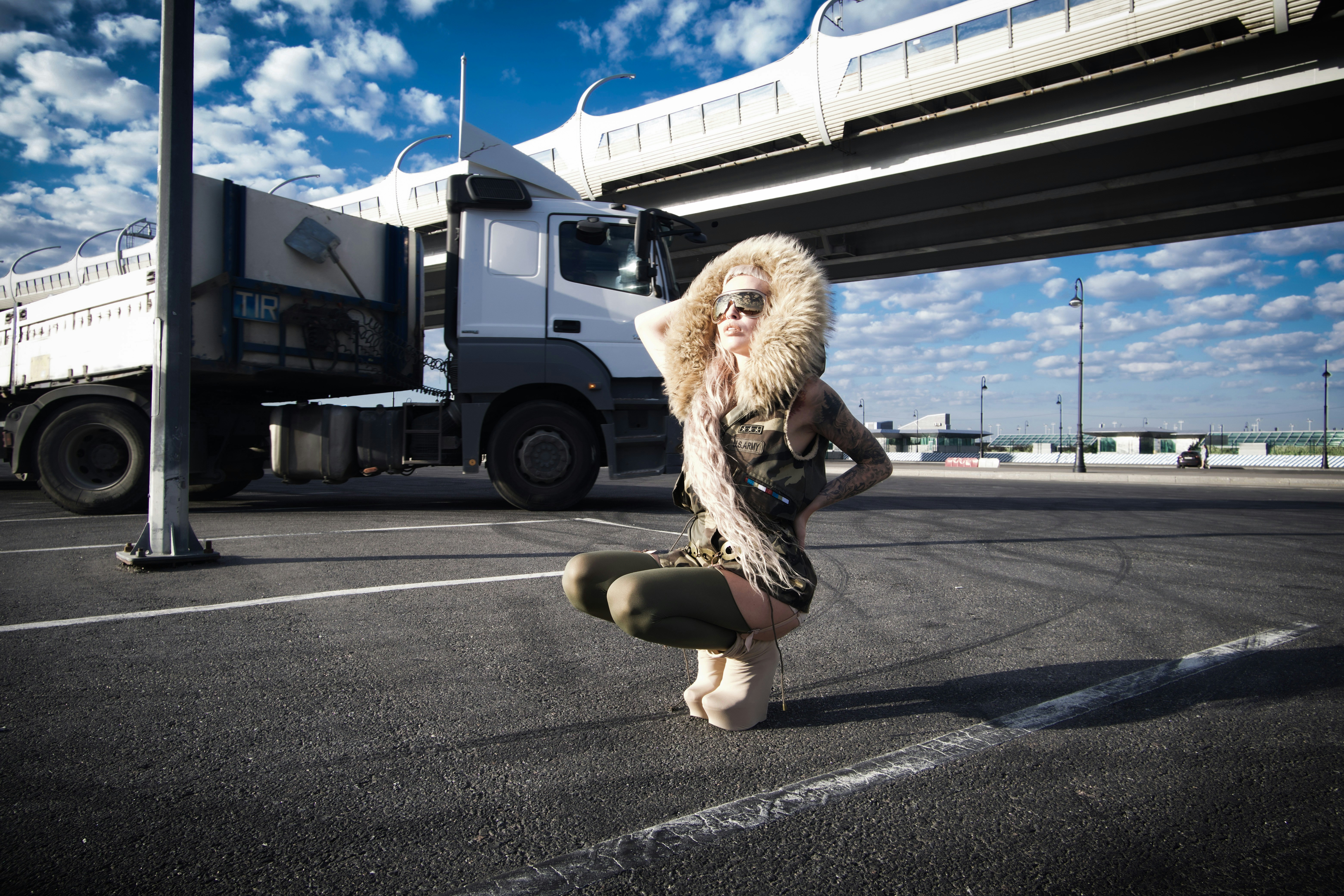 Under the Overpass: fur-hooded street dancer halts mid-jump in the parking lot