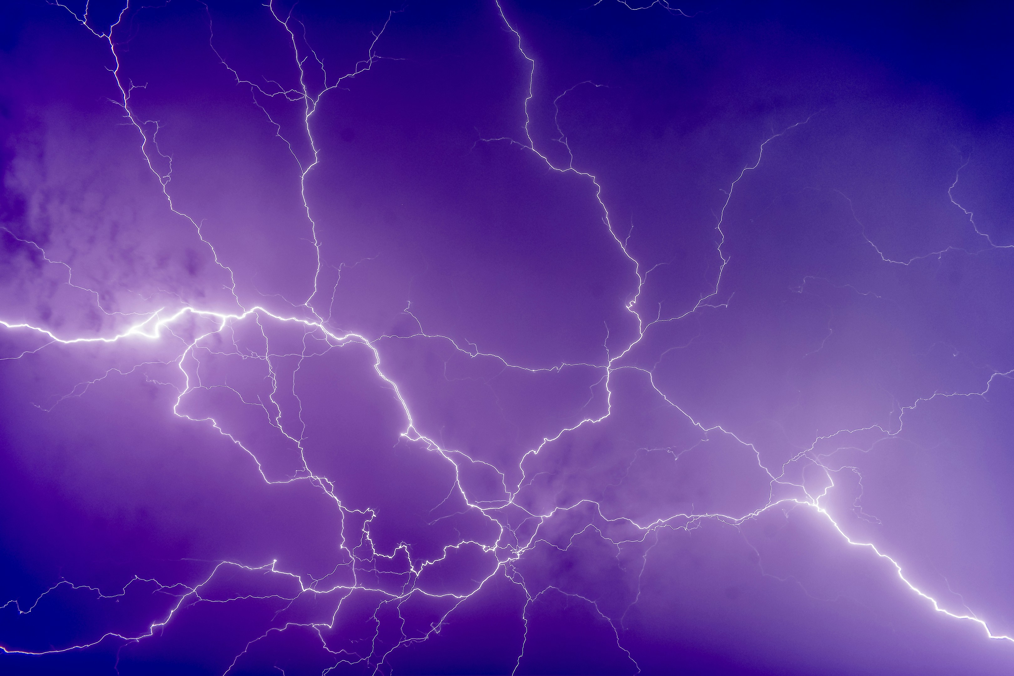 Vibrant purple lightning branches across a darkened sky.