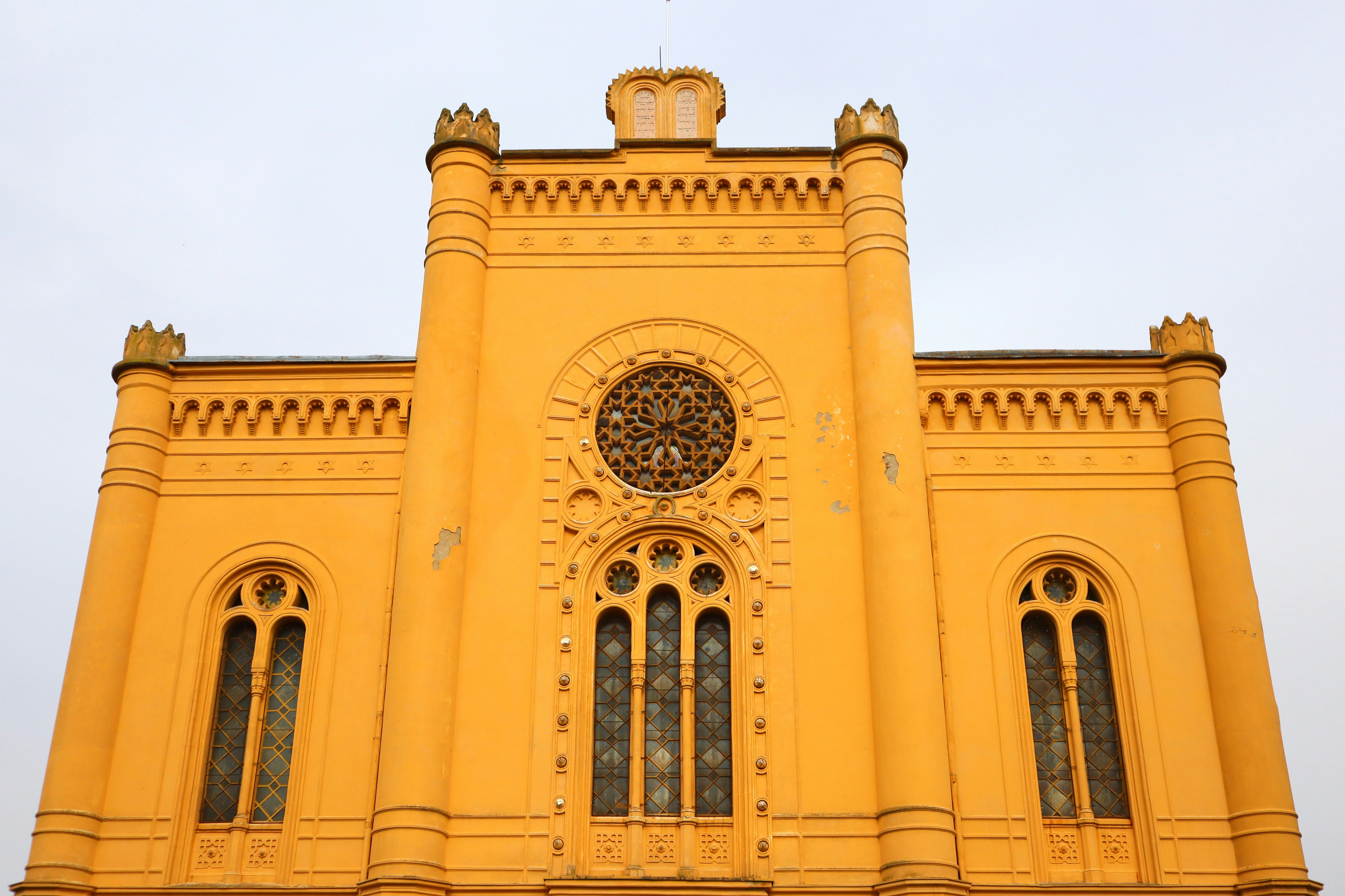 Golden Rose at the Apex: Central Circular Window on a Sunlit Orange Facade