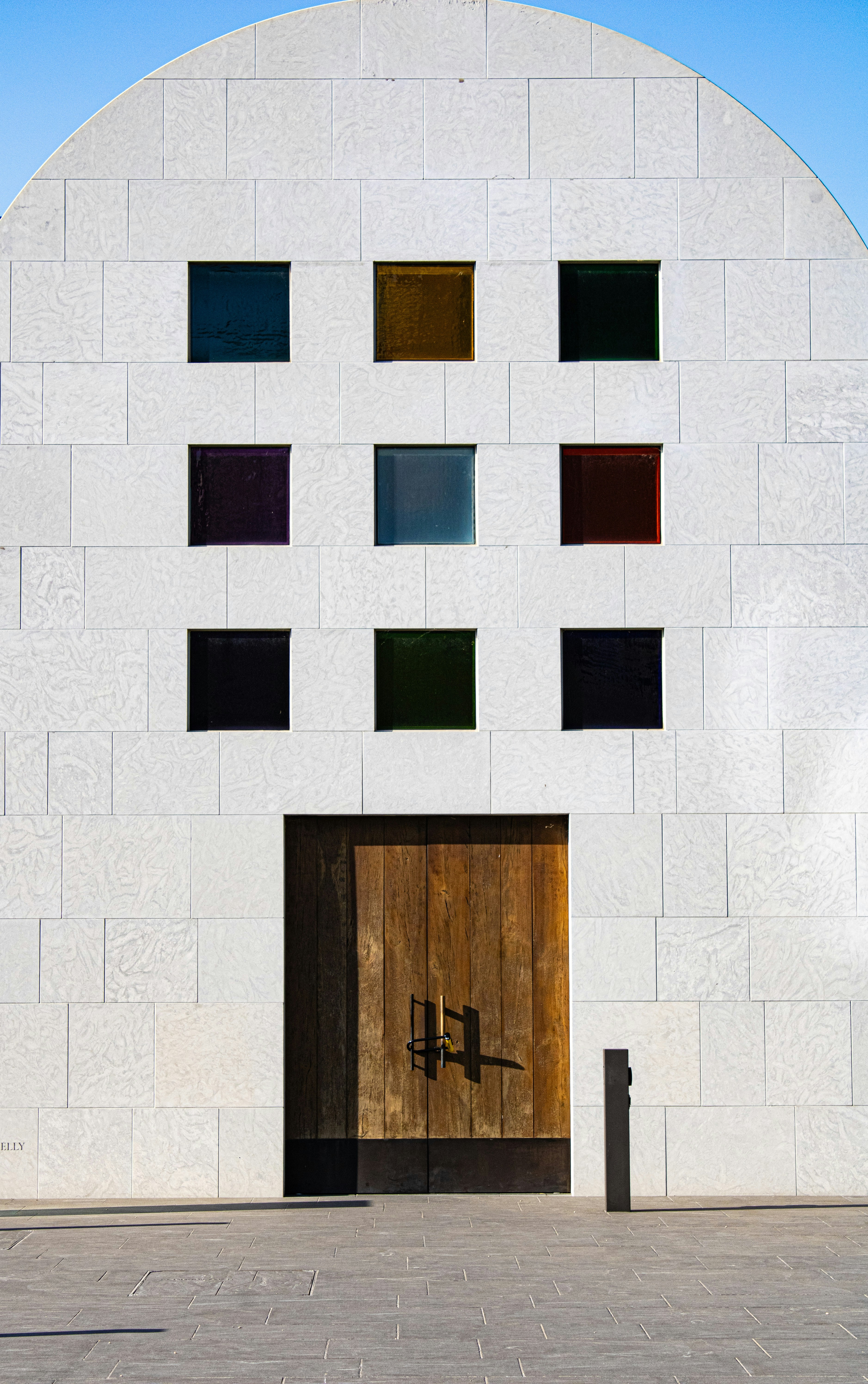 Polished Geometry: A White Facade with Colored Square Windows and a Sturdy Wooden Door
