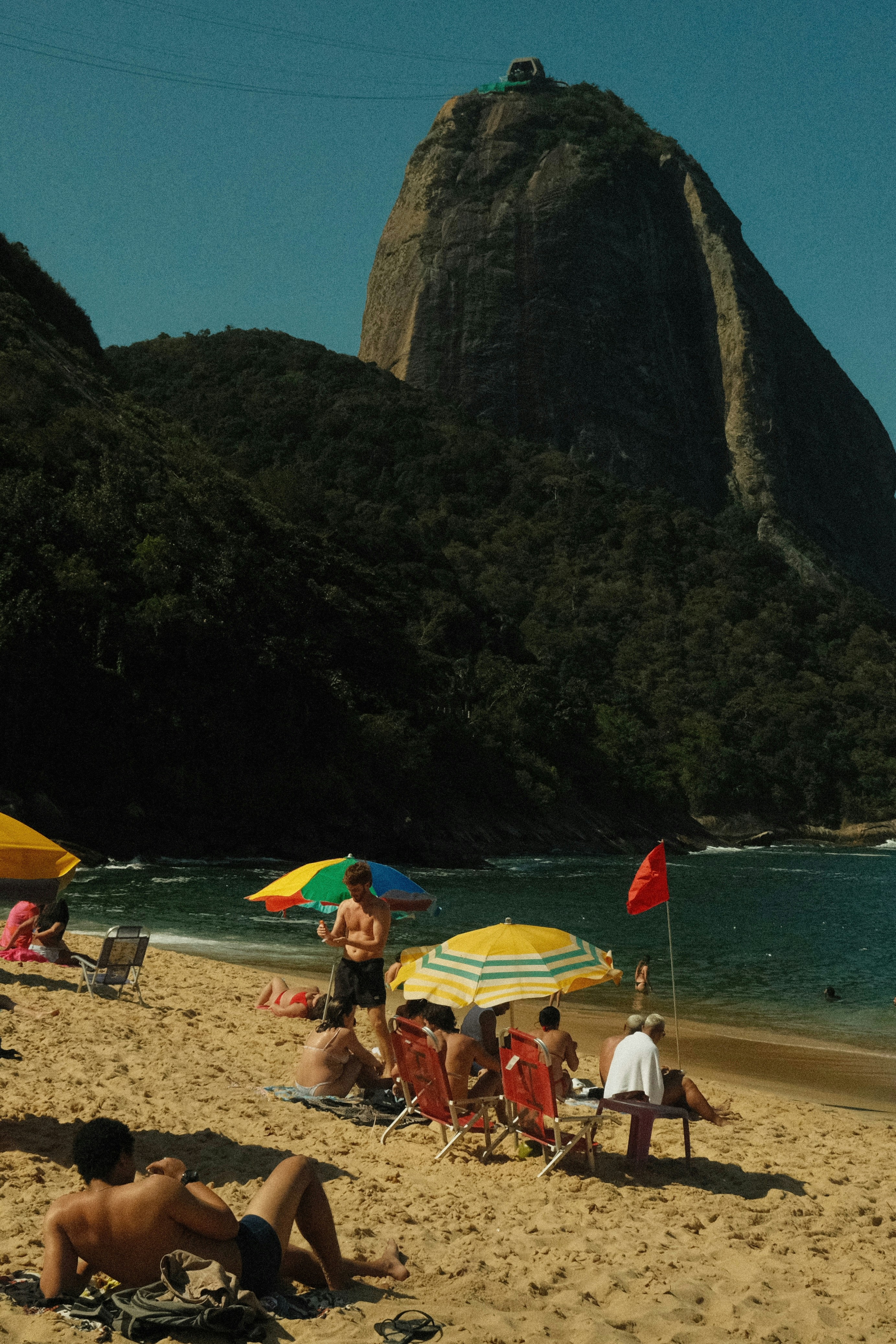 Cable Car Above the Coastal Monolith: A Beach Scene in Quiet Contrast