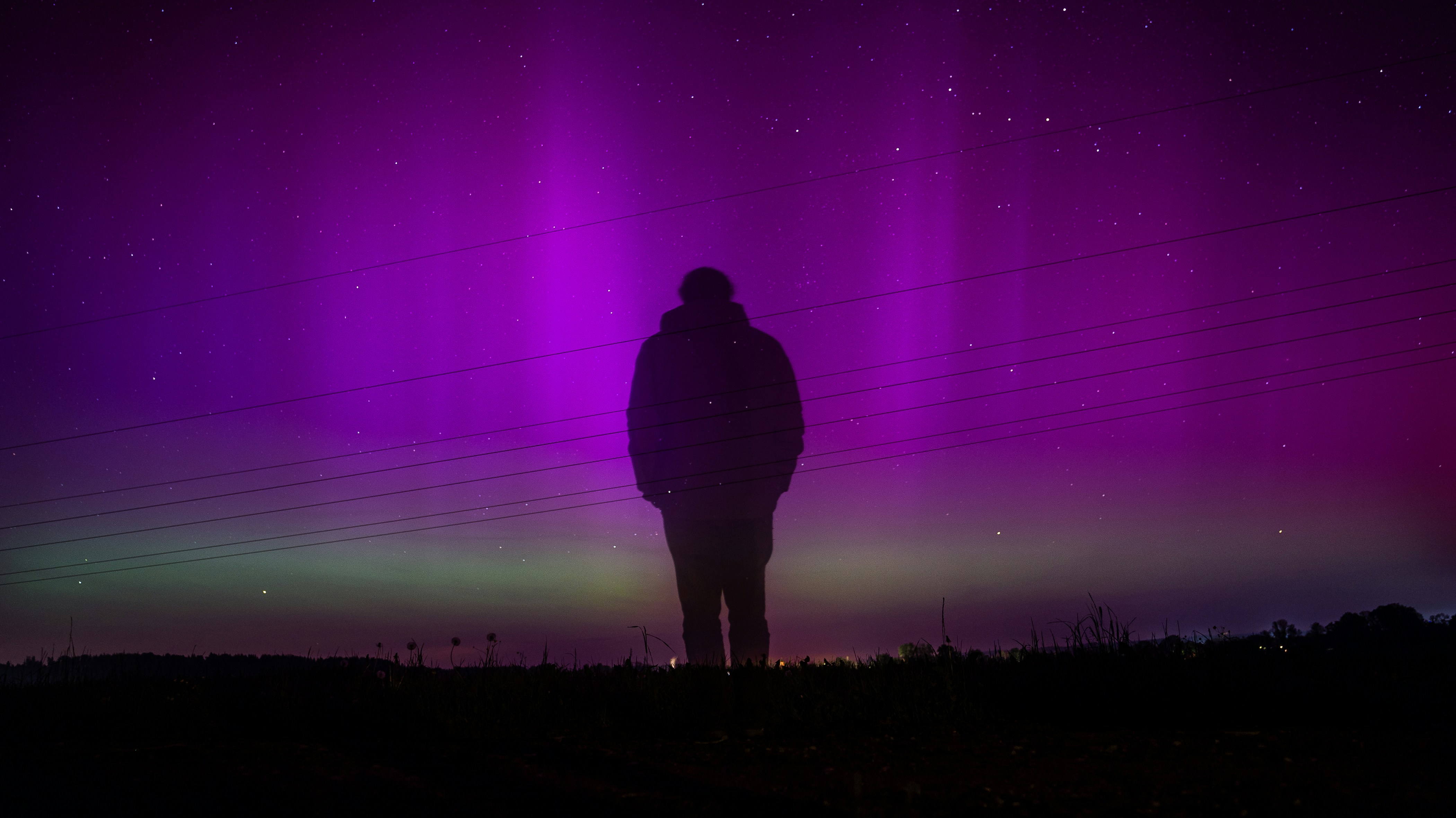 Lone Figure Under Violet Aurora Over Quiet Horizon