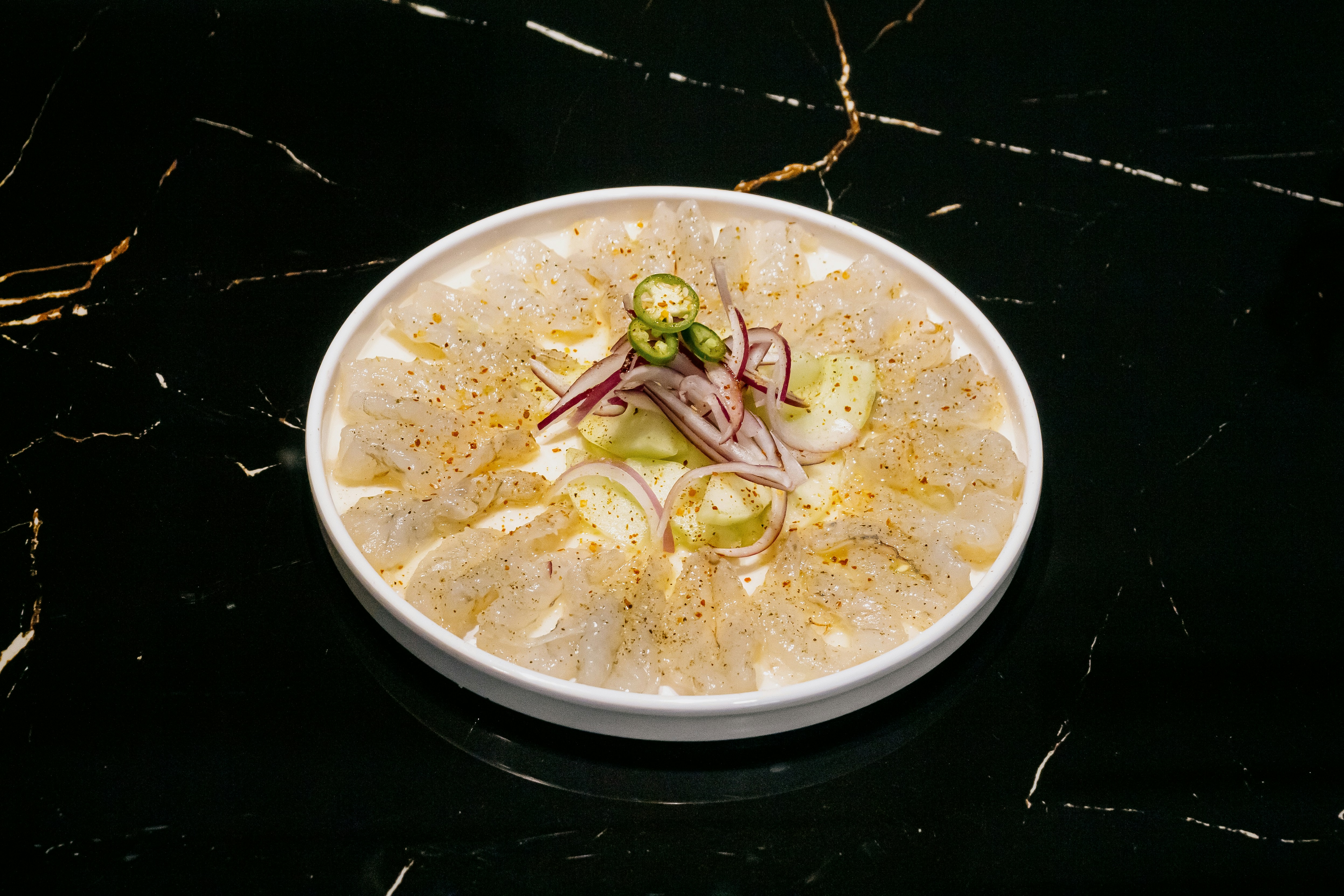 Cucumber Coins and Onion Shreds Crown a Creamy Dip on a Dark Marble Plate