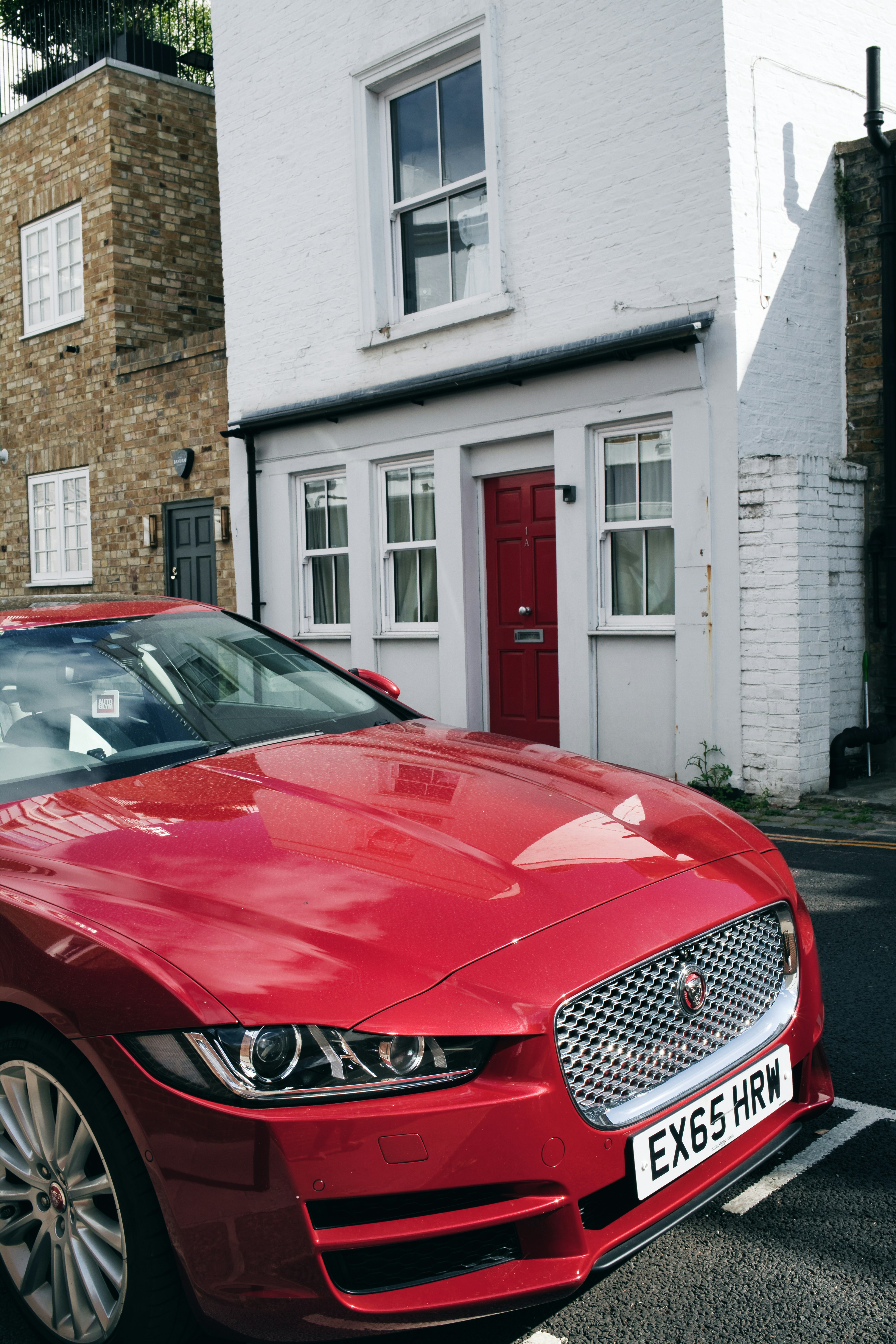 Crimson Jaguar at a White-Walled Street: A Quiet Urban Portrait