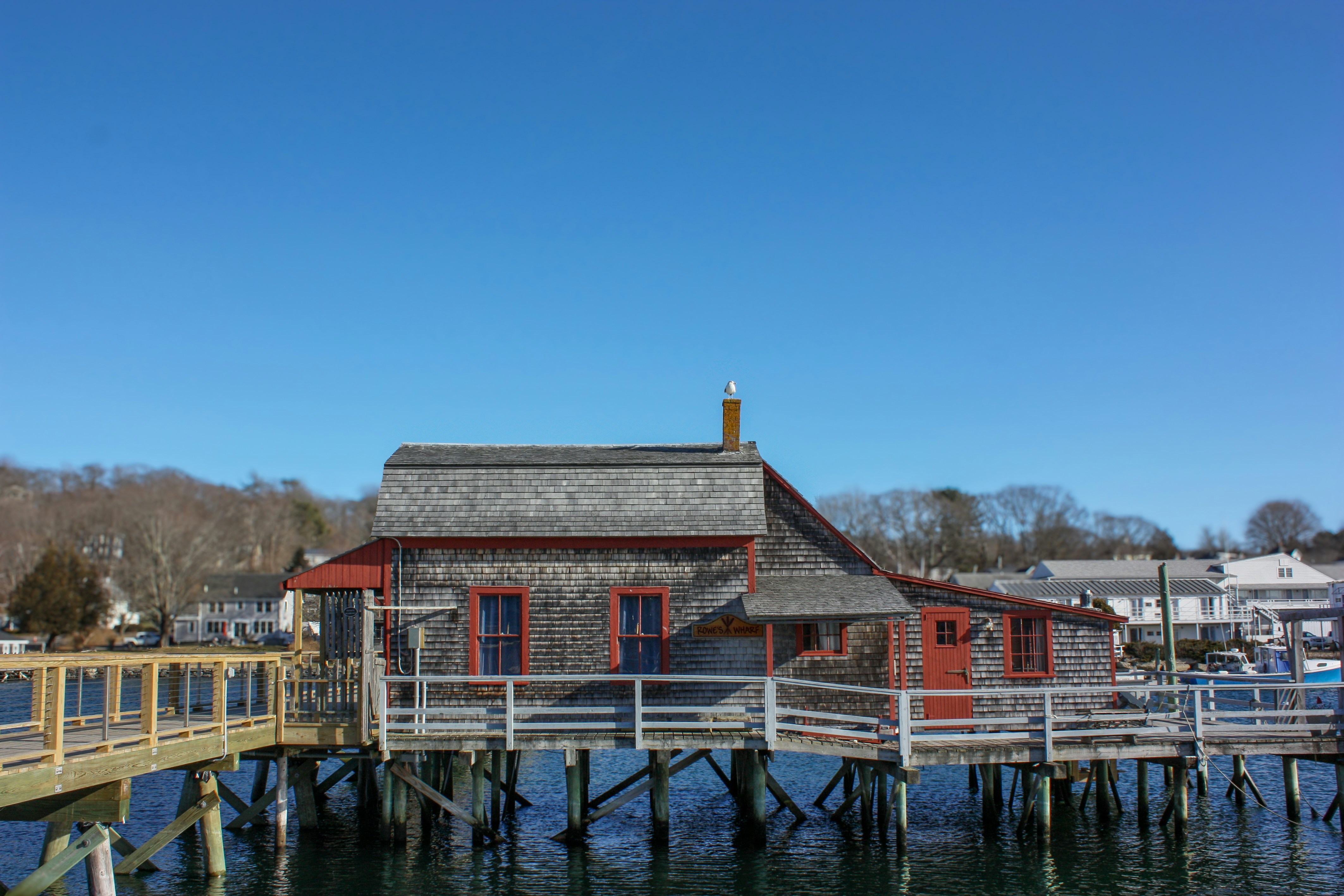 Harbor Boathouse on Stilts: Red Trim Over Quiet Water