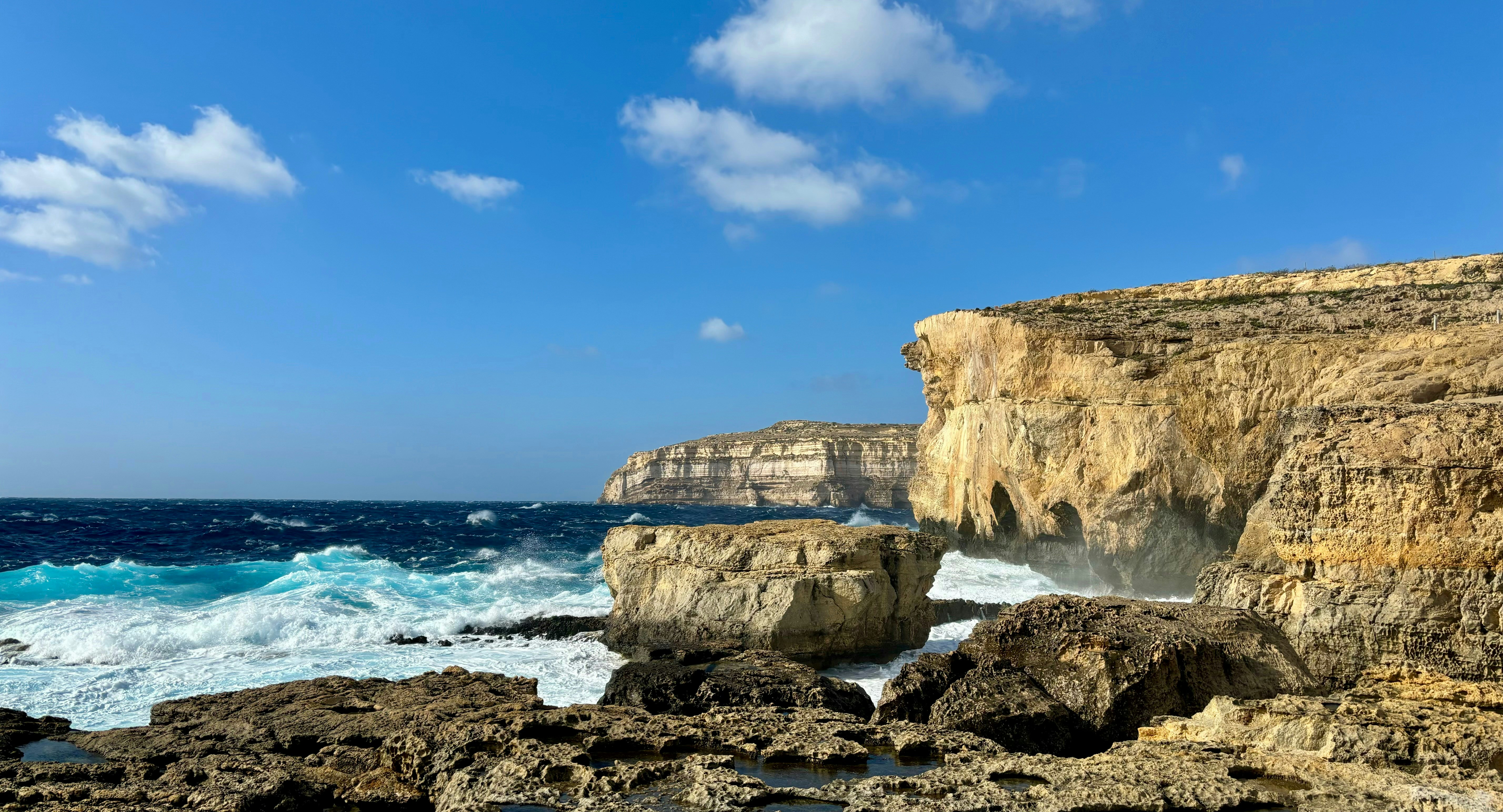 A rocky cliff overlooks the ocean on a sunny day photo – Free Dwejra ...