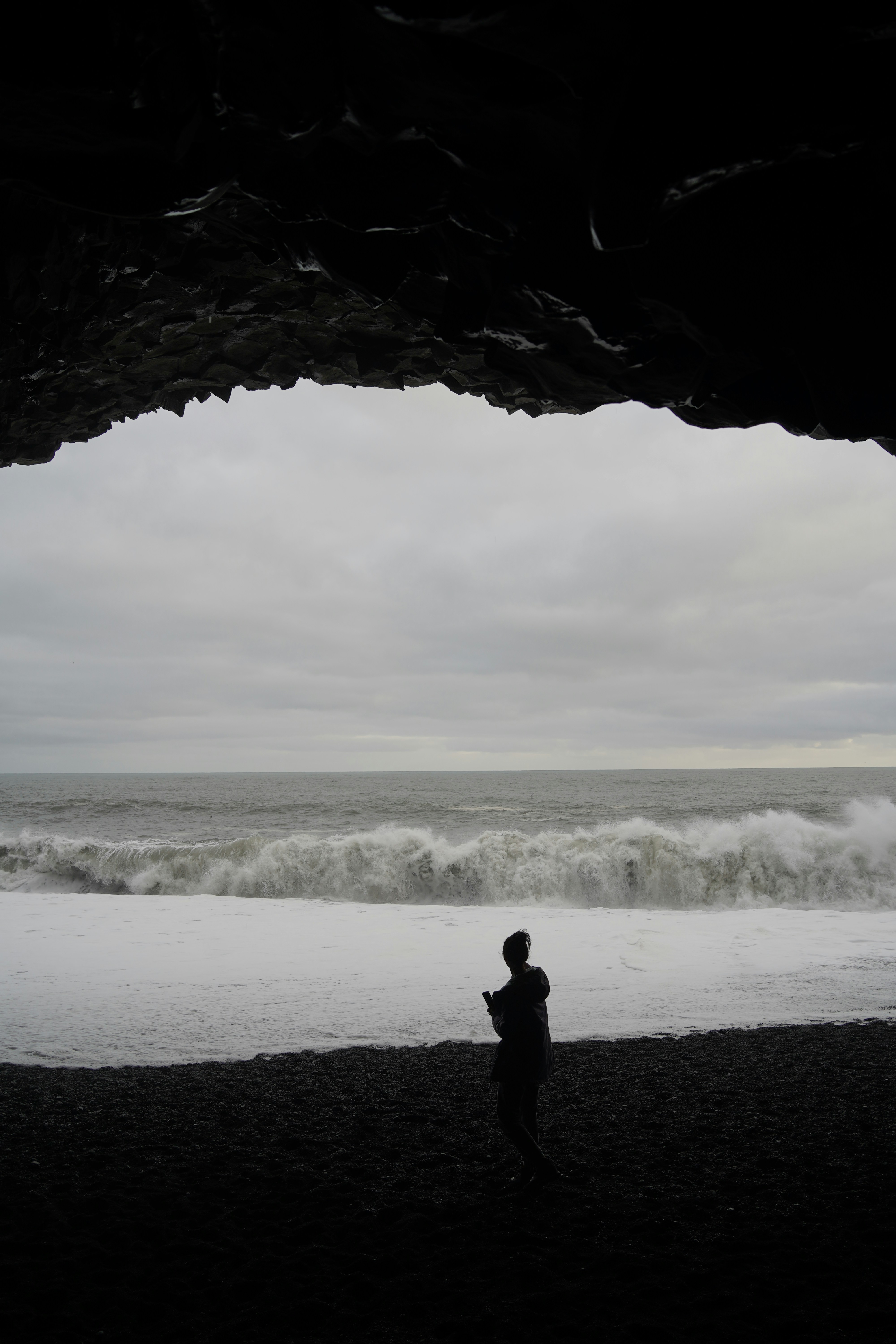 Silhouette at the Sea's Edge Under a Cavernous Arch