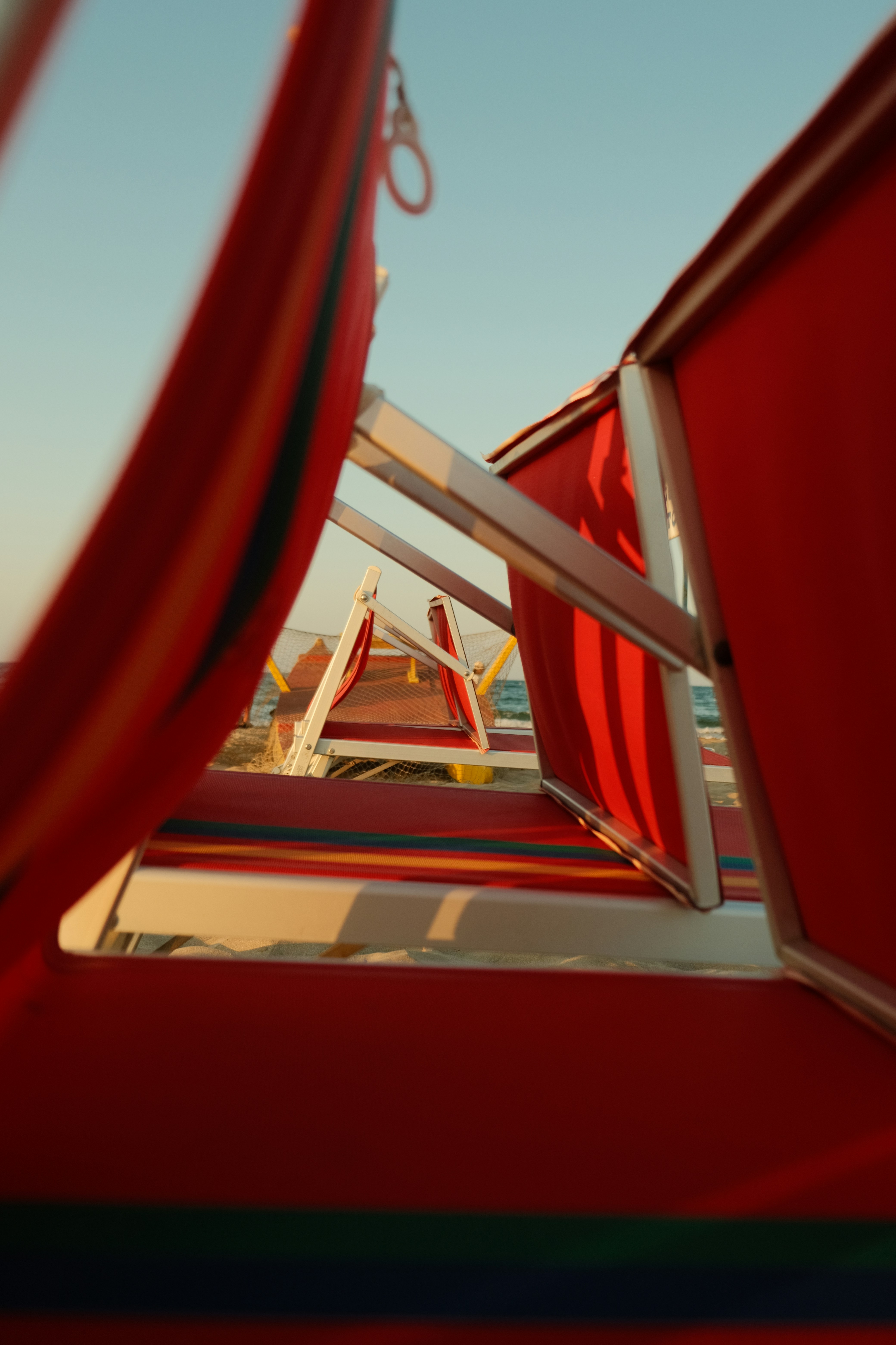 Red Geometry on the Shore: A Sunlit Tunnel of Beach Chairs