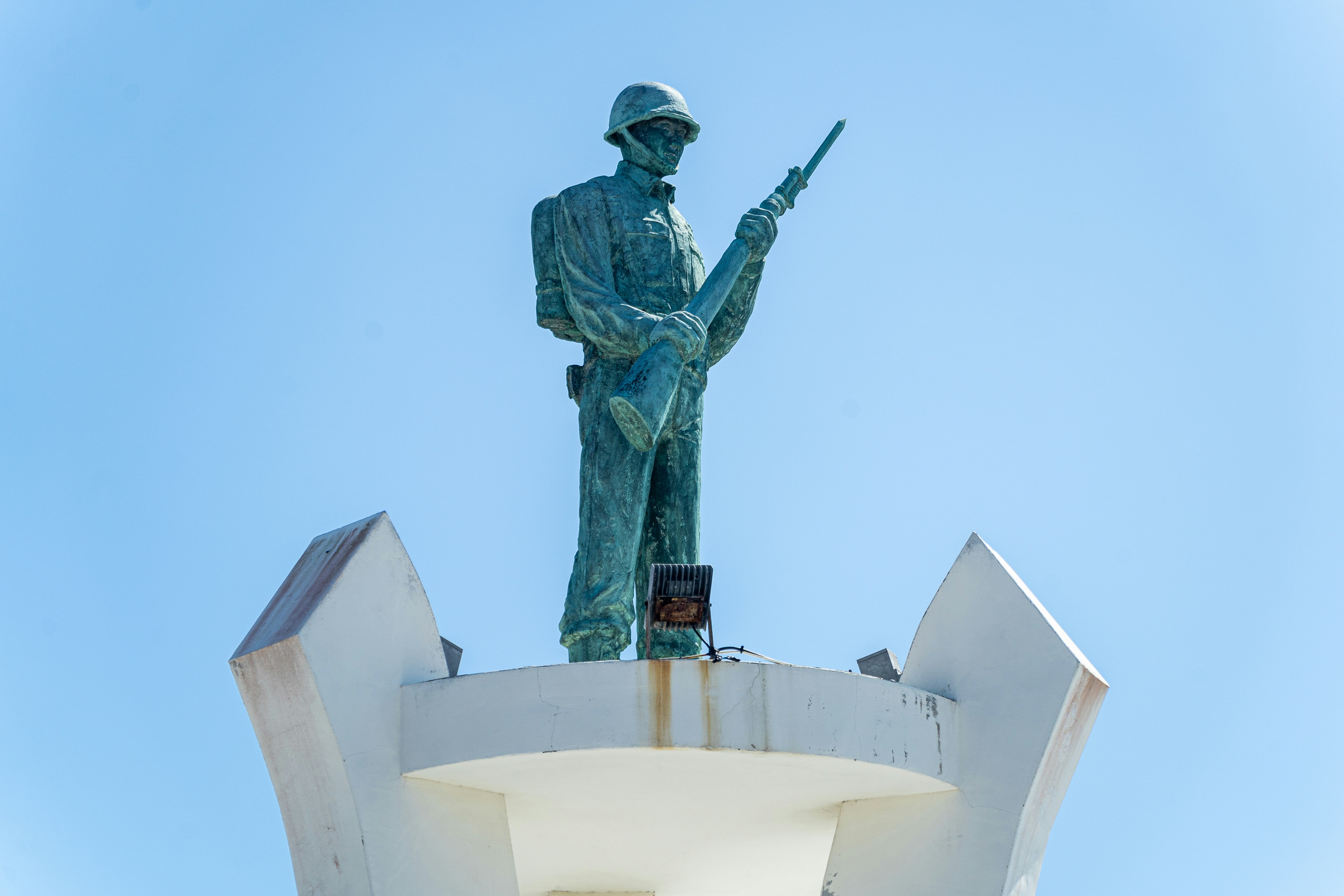 A statue of a man holding a gun on top of a building photo – Free Art ...