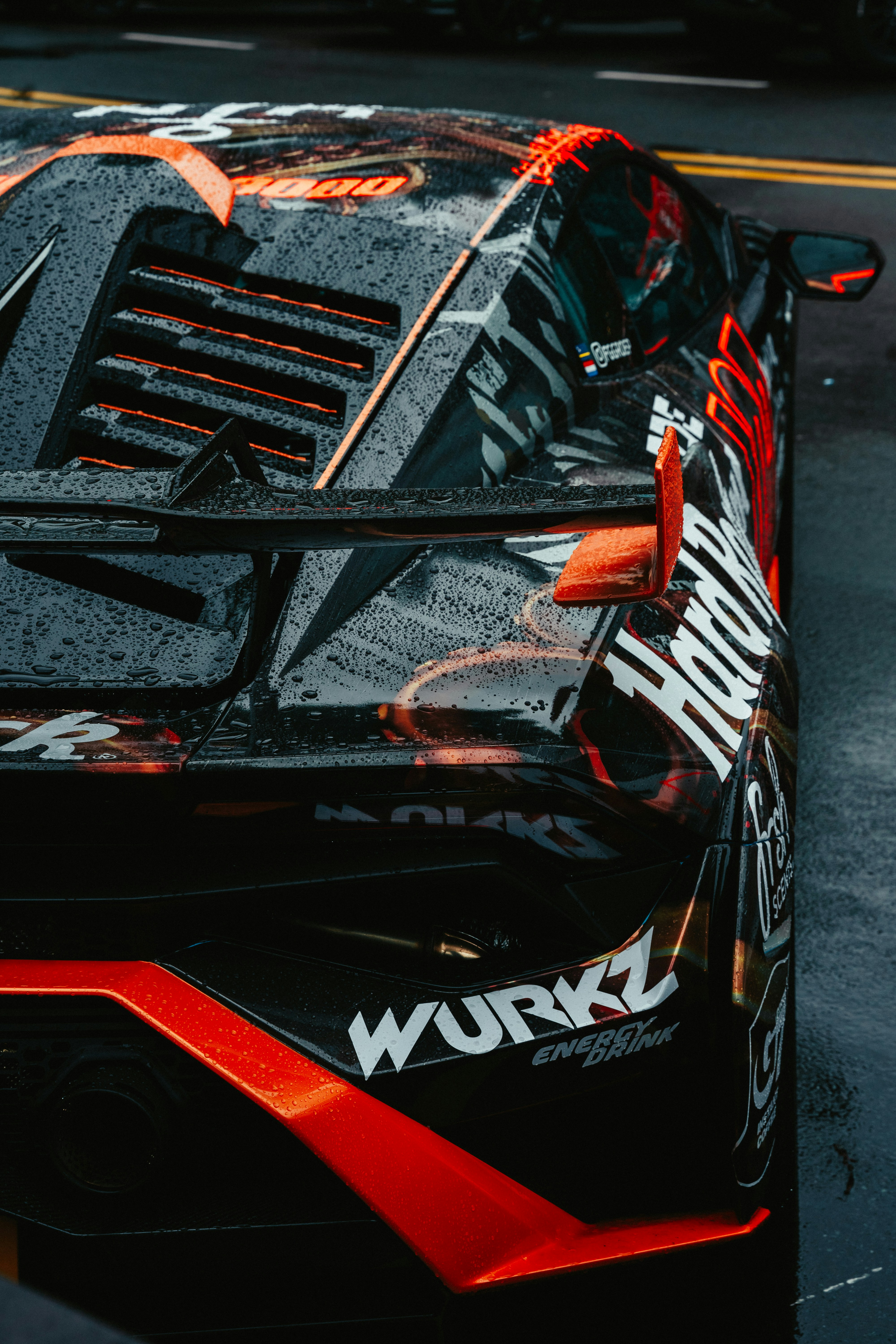Rain-Kissed Neon Lines: A Close-Up of a GT Racecar's Rear Quarter