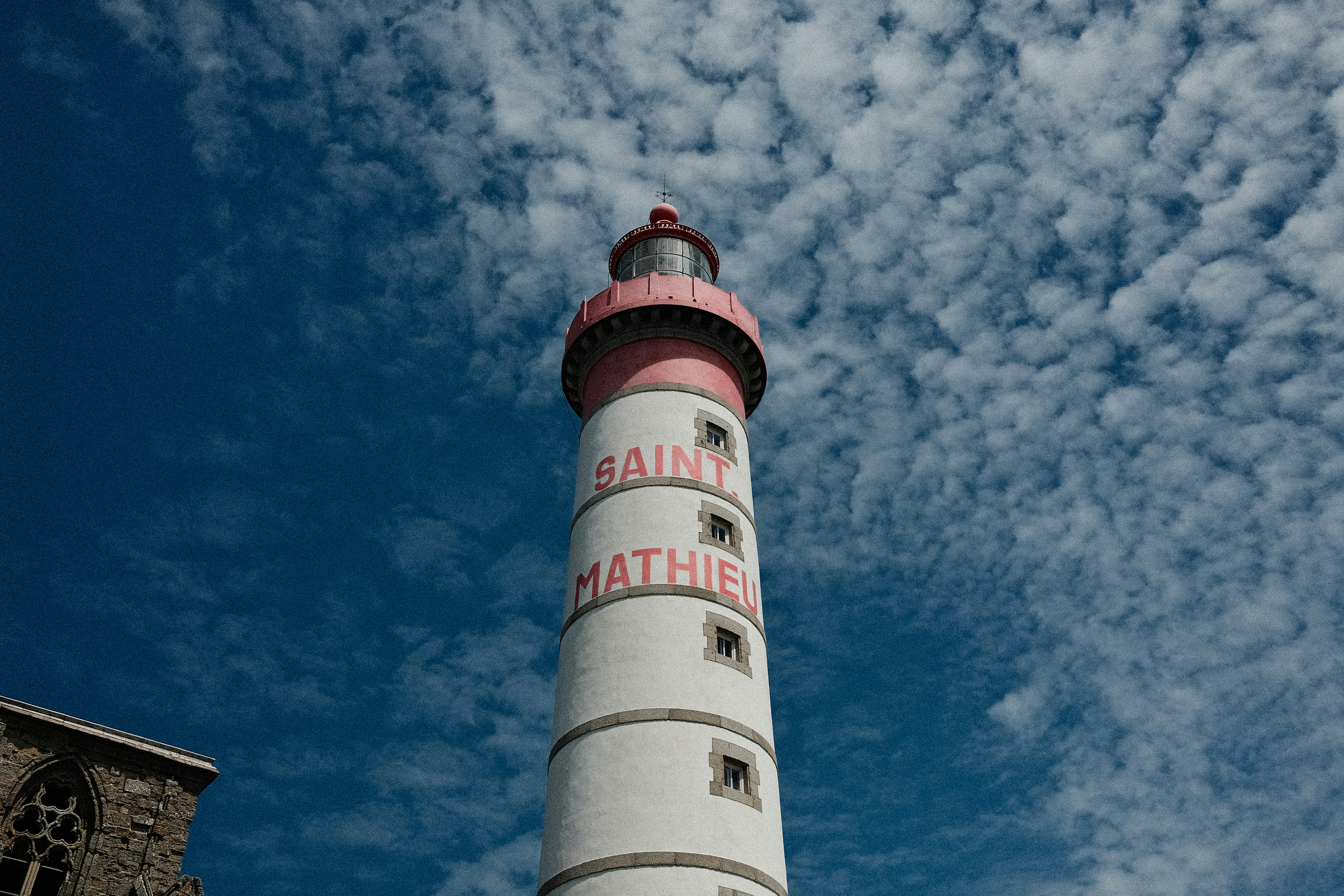 Sentry of the Sea: A Red-Capped Lighthouse Reaching Toward a Cerulean Sky