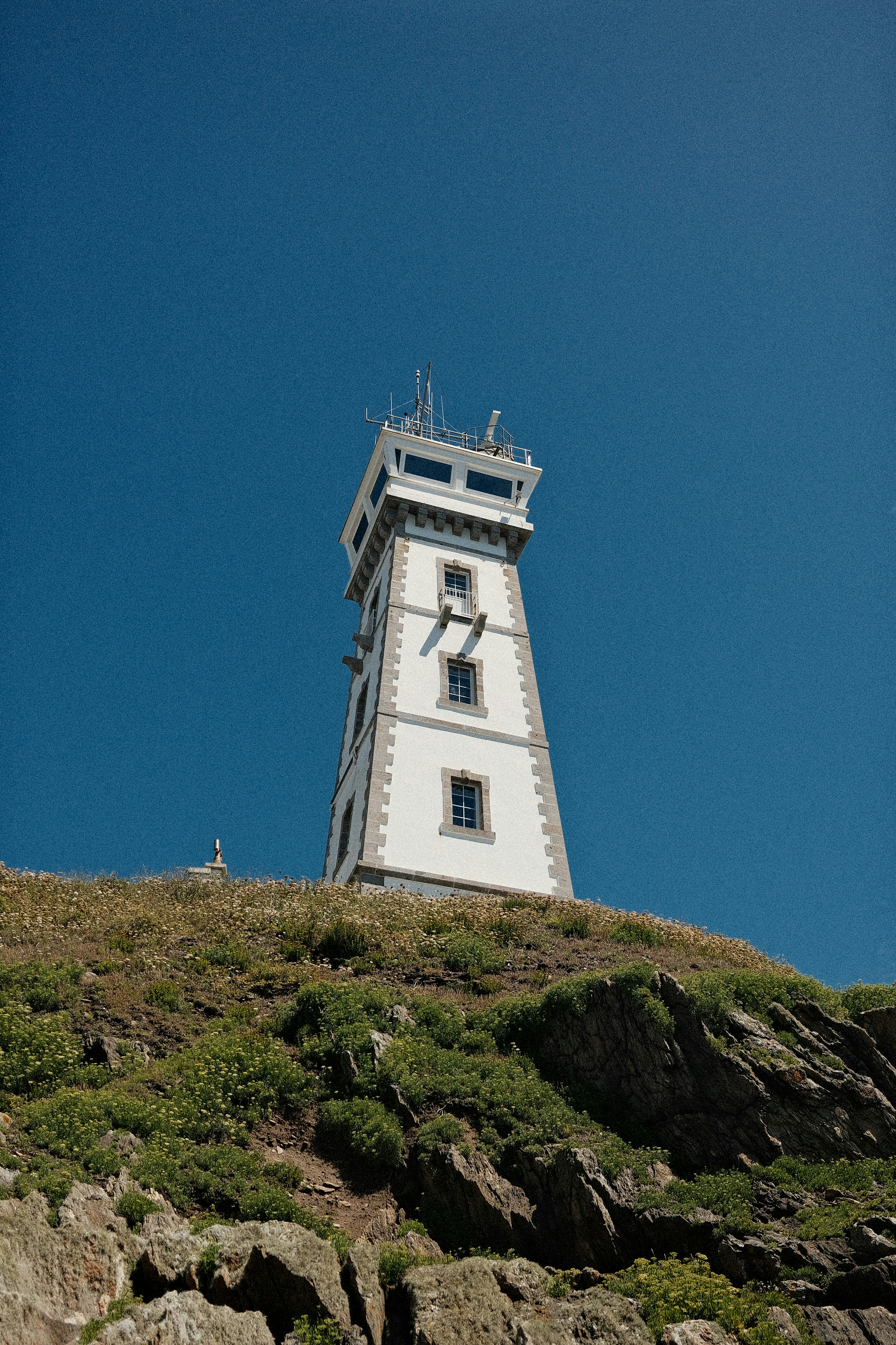 Beacon on a Cliff: A White Lighthouse Against a Bold Blue Sky