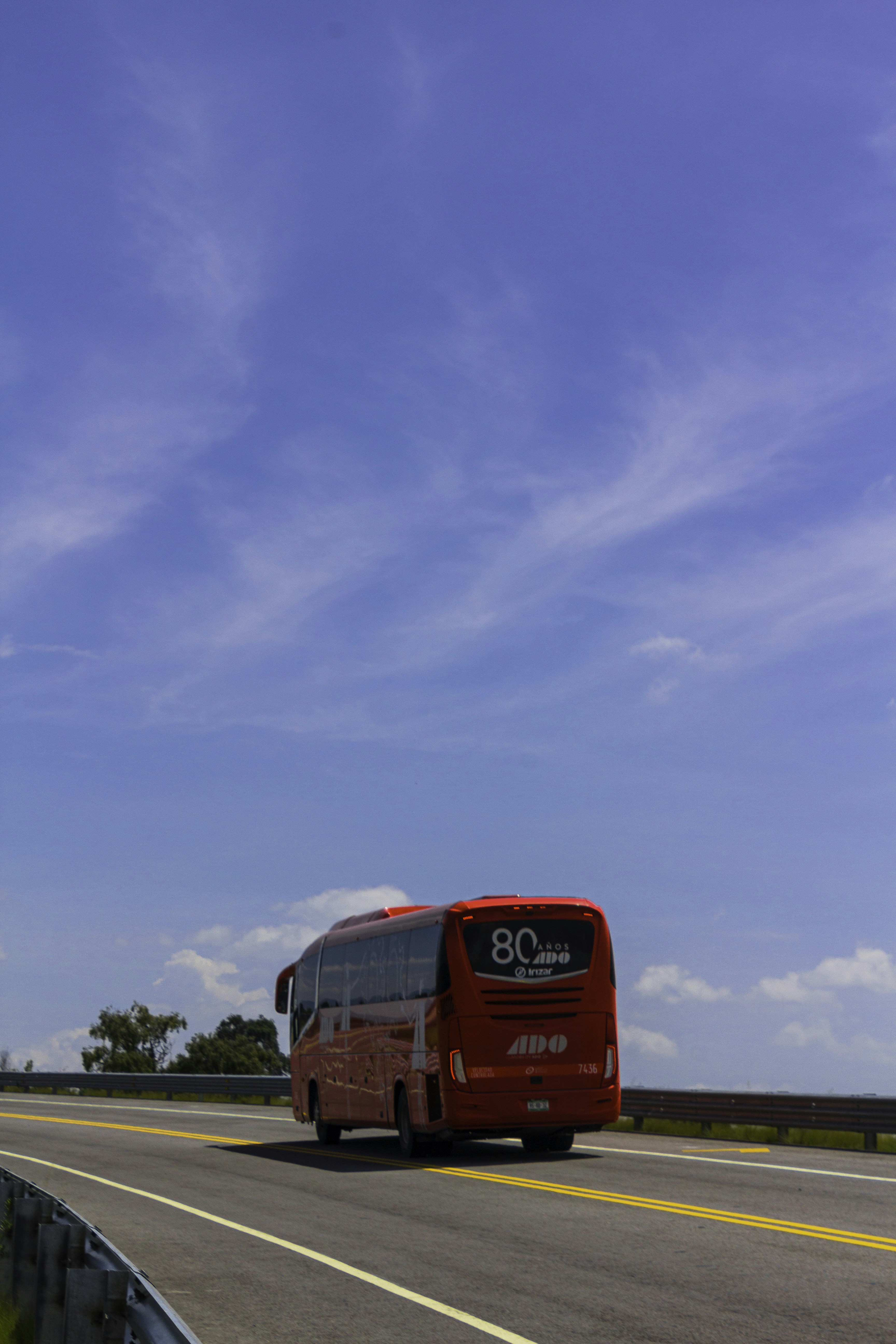 A red bus driving down a highway under a blue sky photo – Free San josé ...