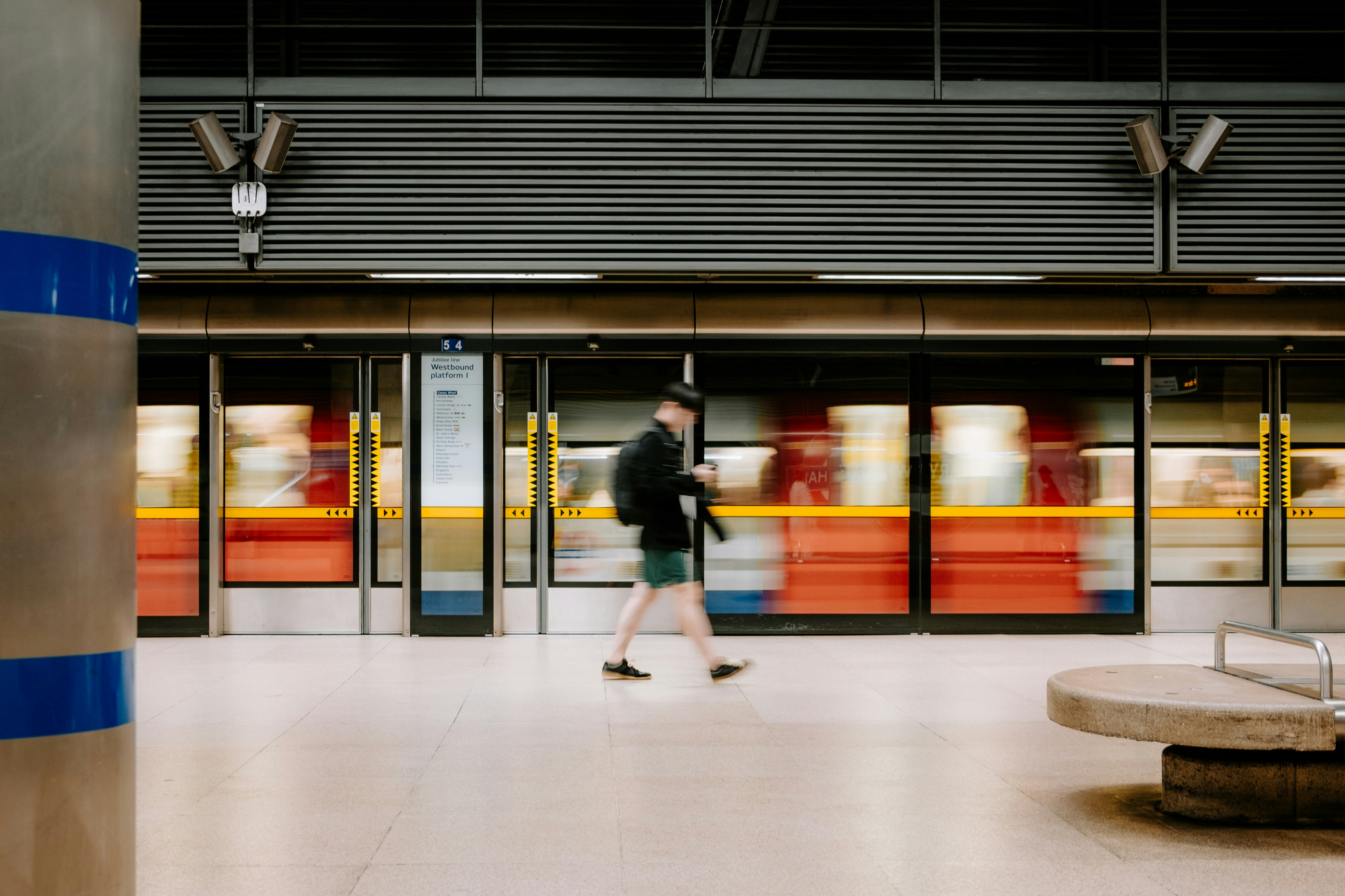 A man walking through a train station next to a train photo – Free ...