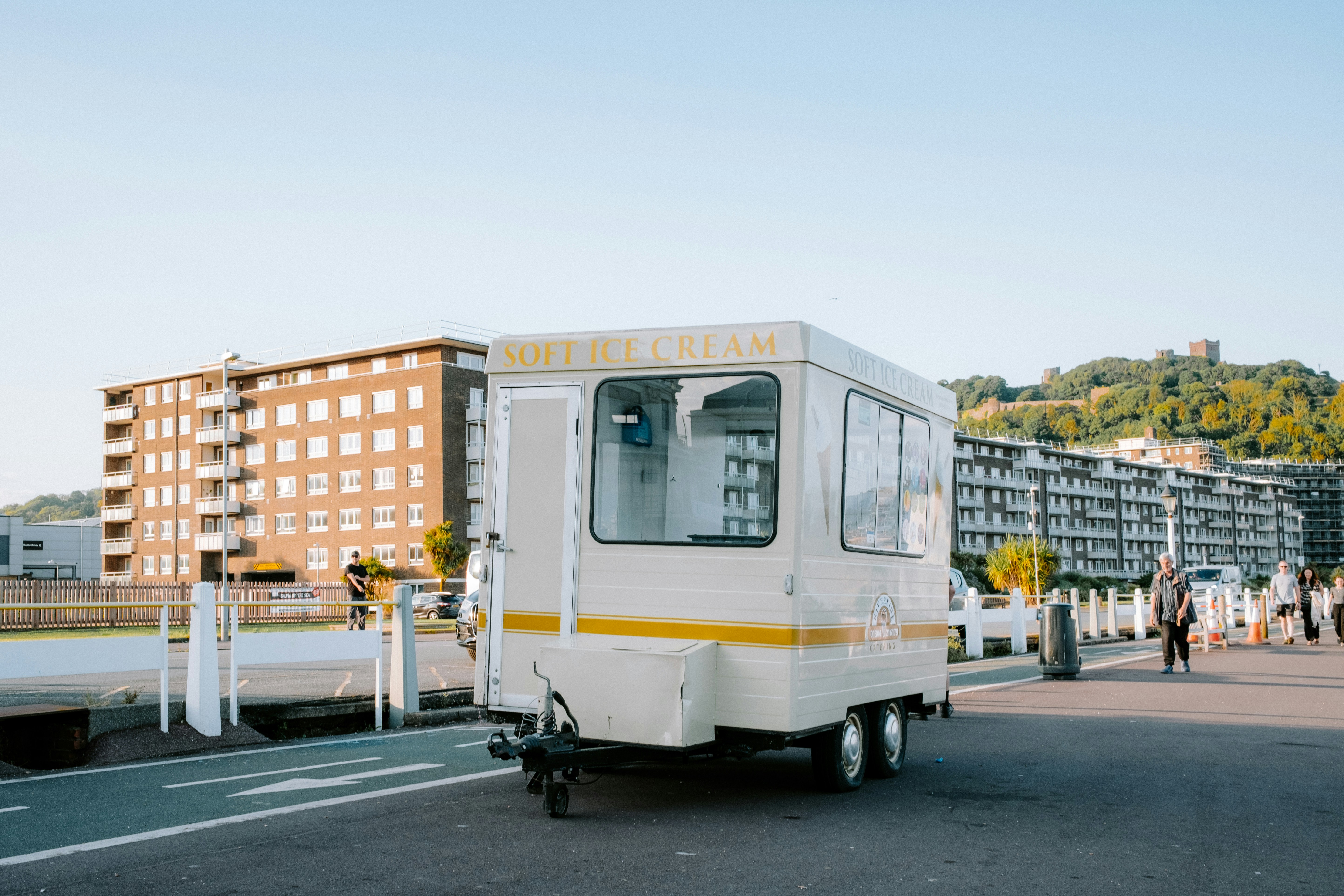 A solitary food truck parked on a quiet city street with apartment buildings in the background.