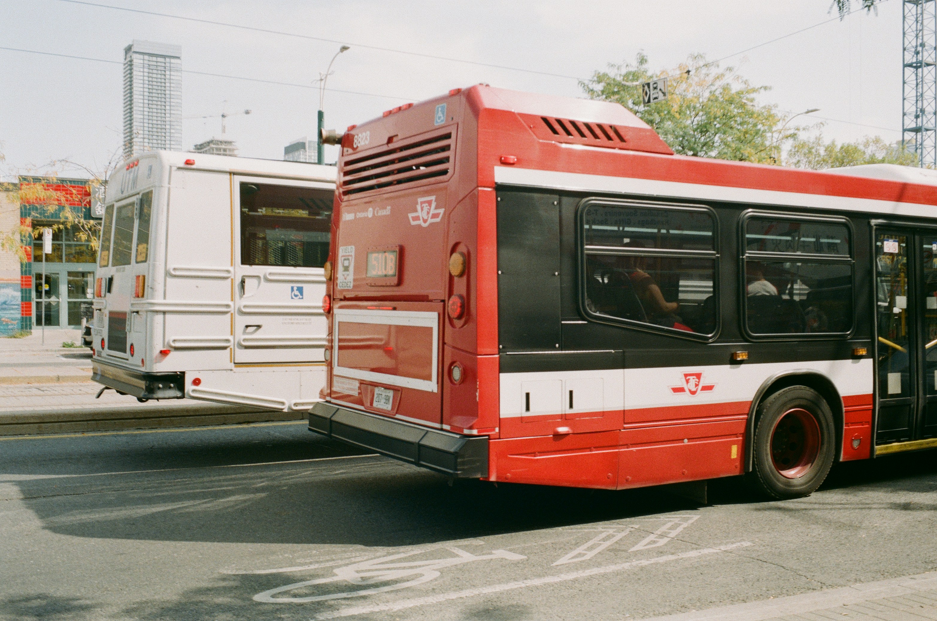 A red and white bus driving down a street photo – Free Shot on film ...