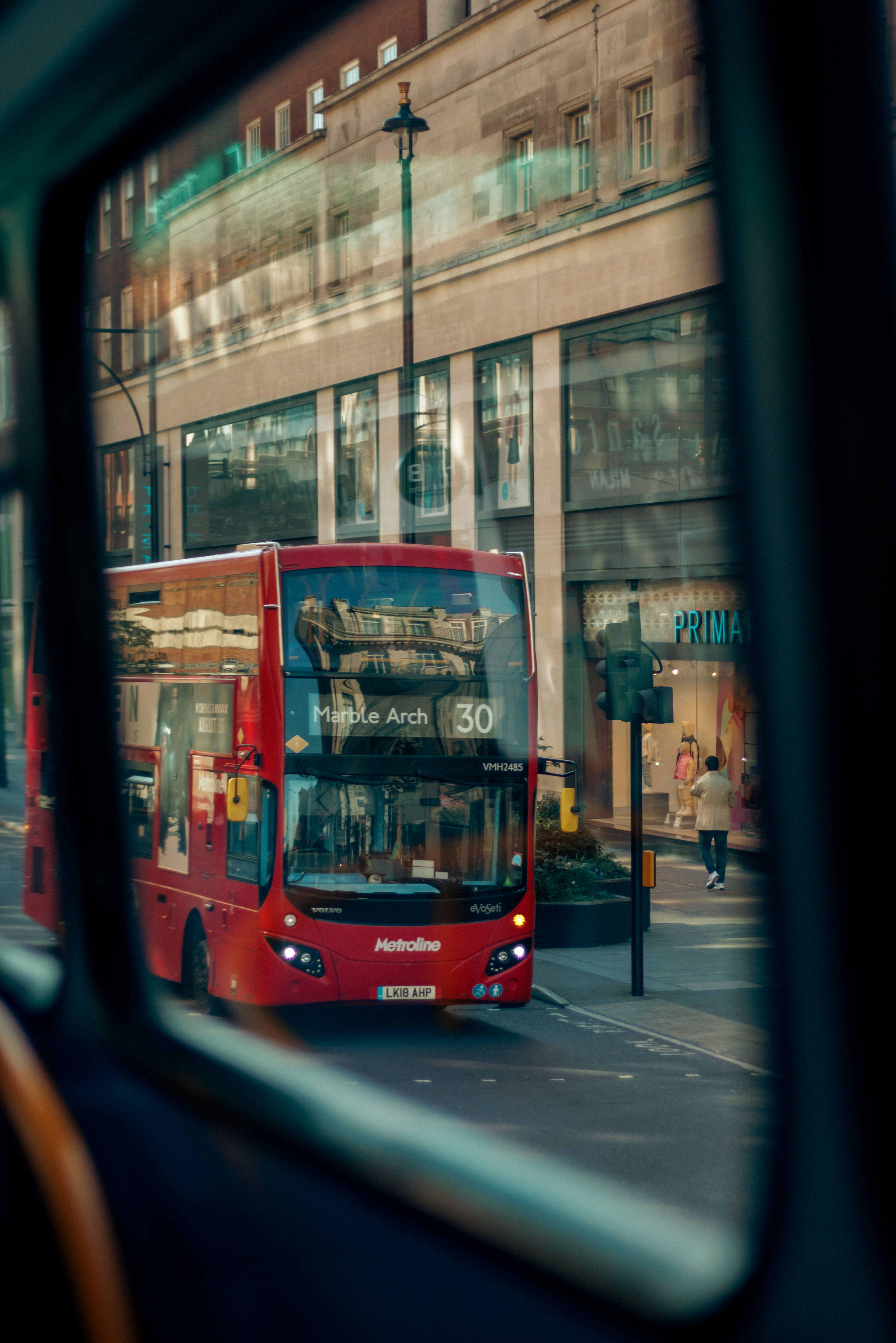 A red bus driving down a street next to a tall building photo – Free ...