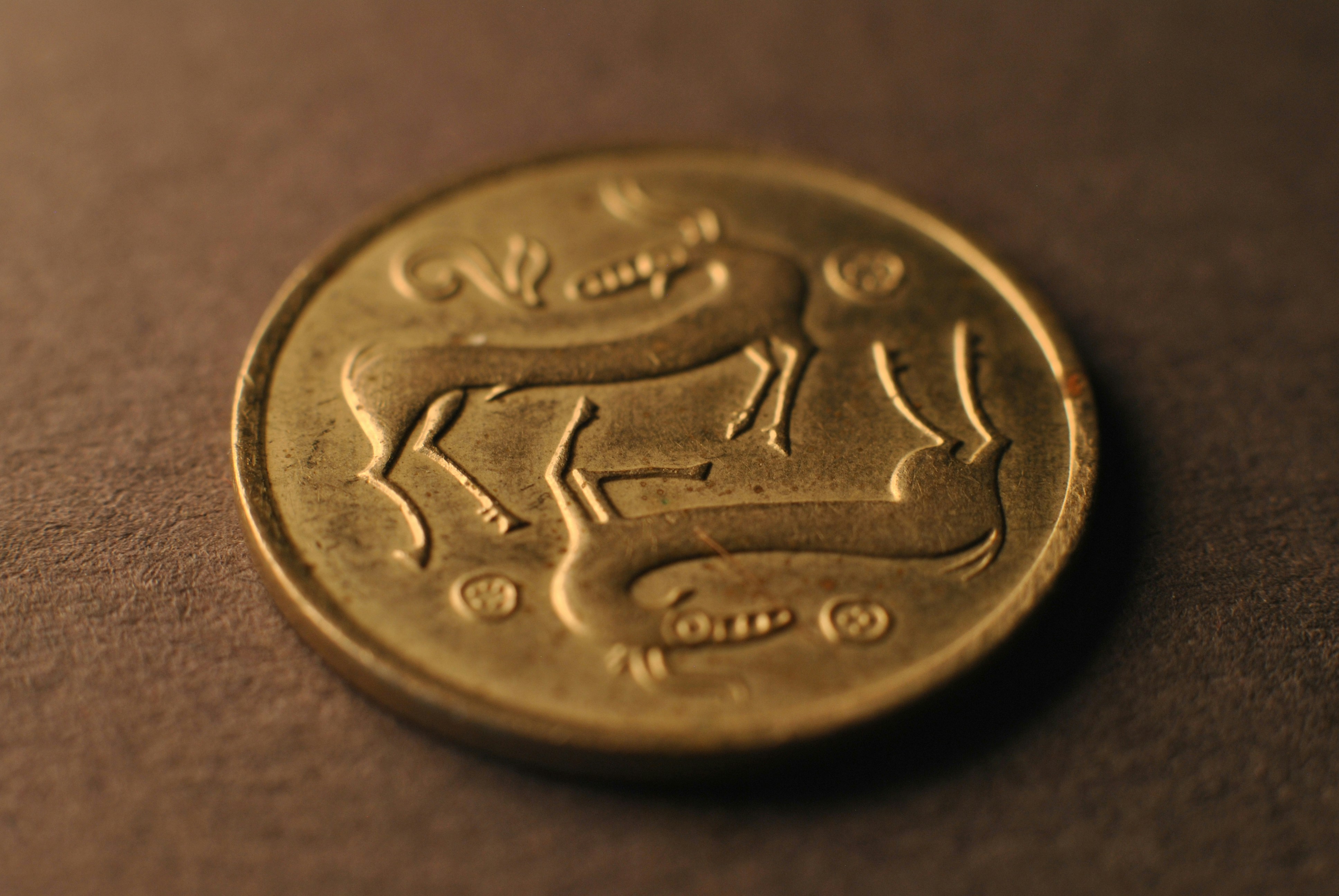 Bronze Coin Close-Up: Arabic Script and a Galloping Horse Motif in Warm Macro Light