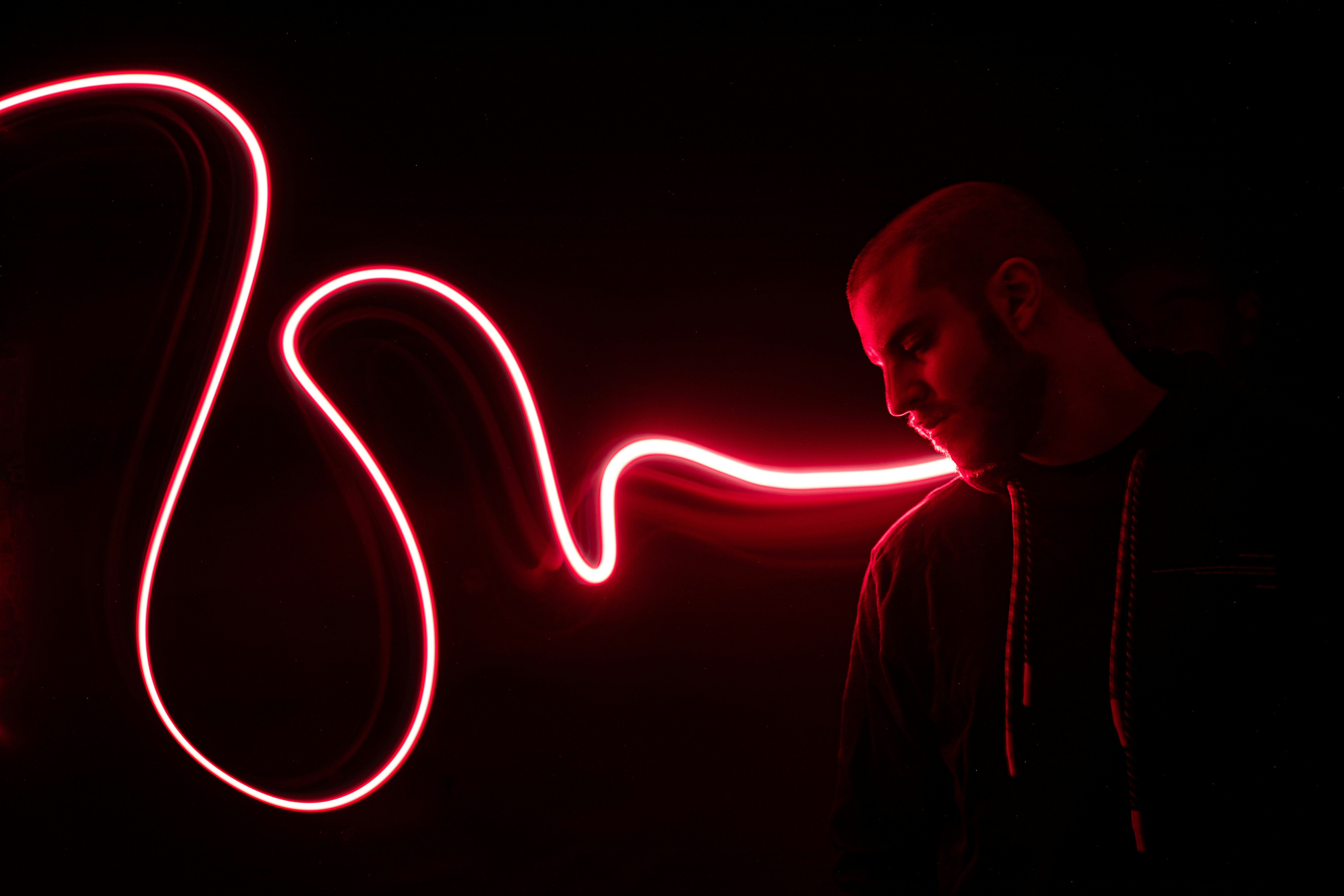 Neon Ribbon Portrait: Red Light Trails Embrace a Quiet Figure