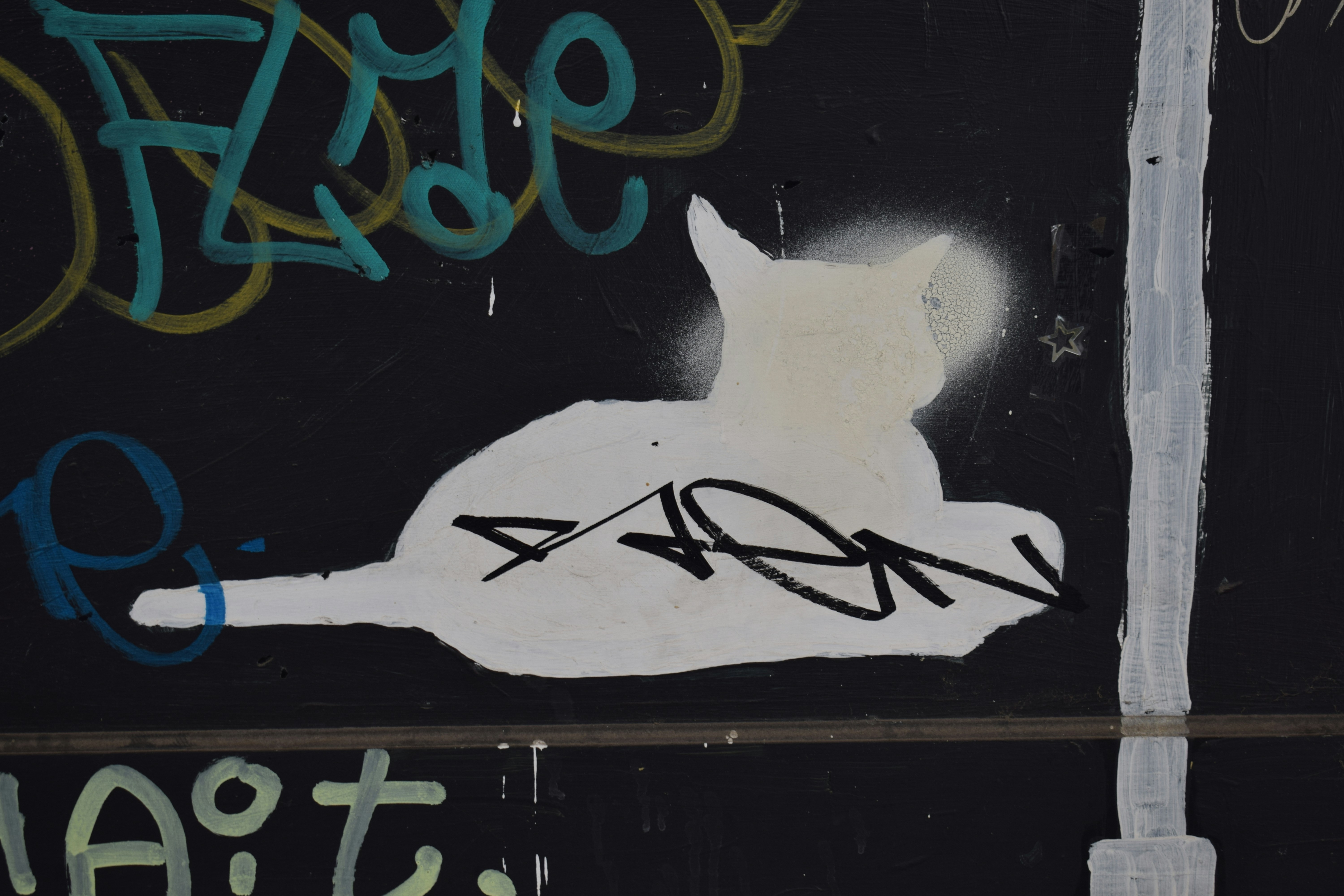 White cat silhouette graffiti resting on a dark wall
