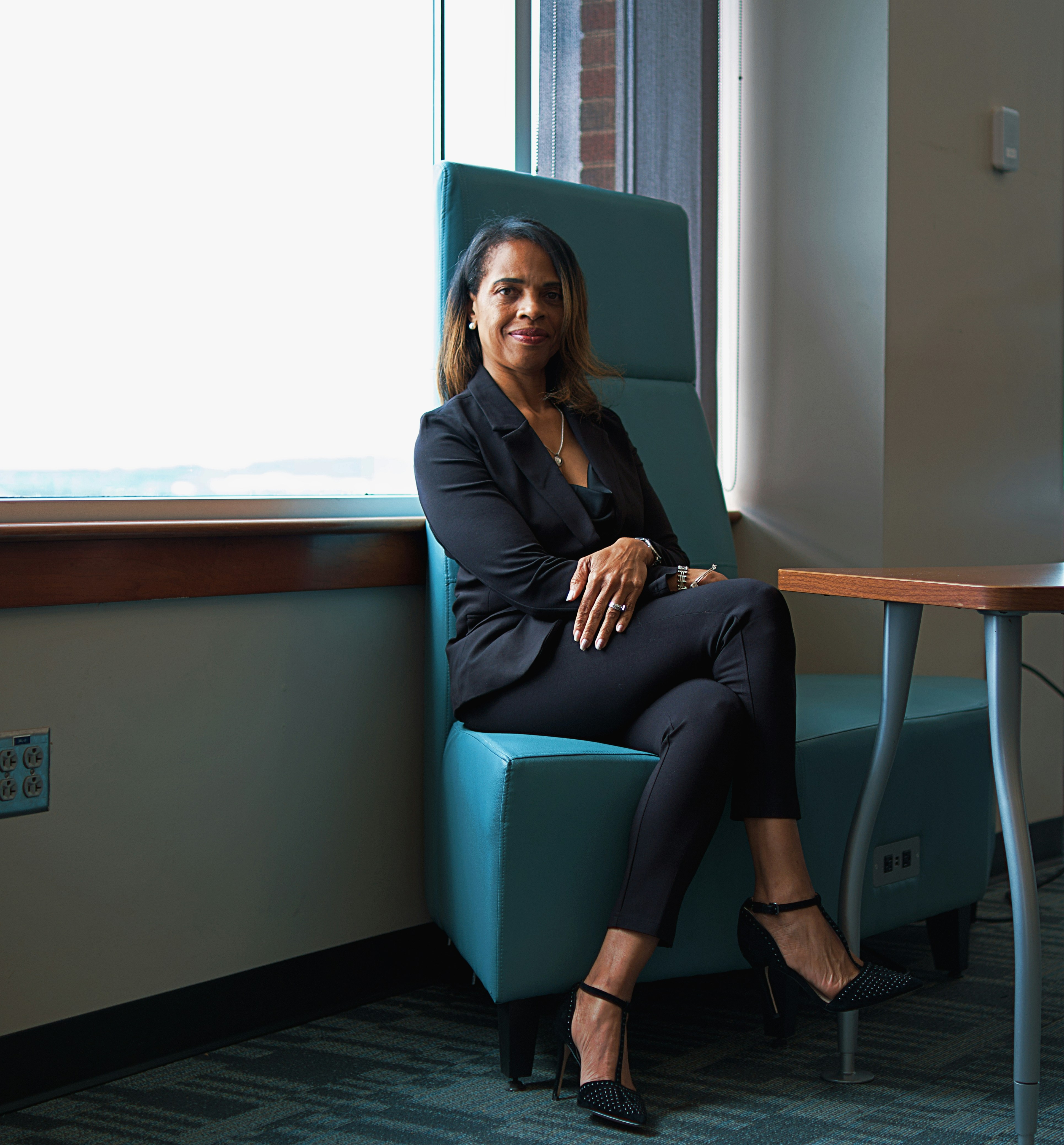 A woman sitting in a blue chair next to a table photo – Free Woman ...
