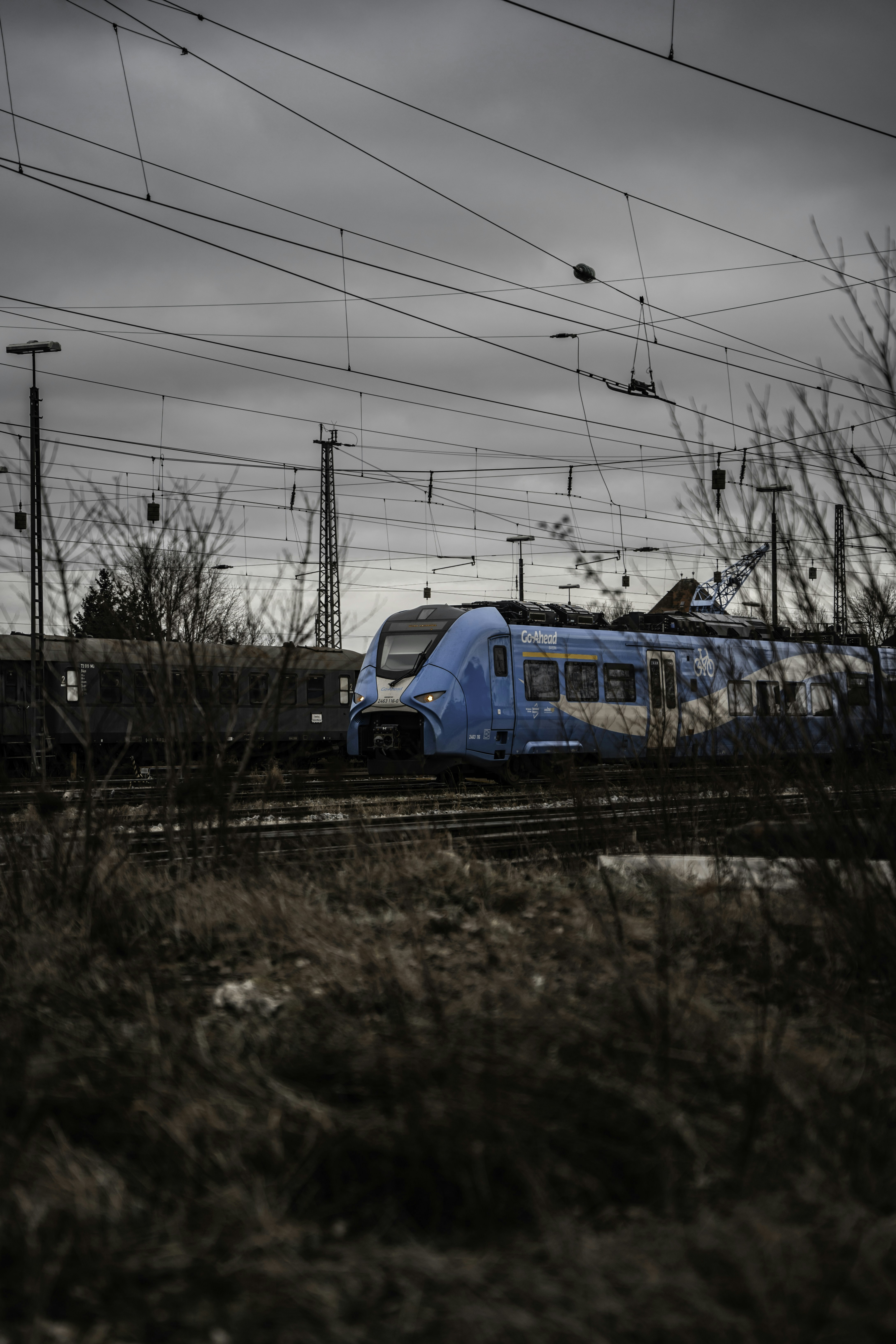 A blue train traveling down train tracks under a cloudy sky photo ...