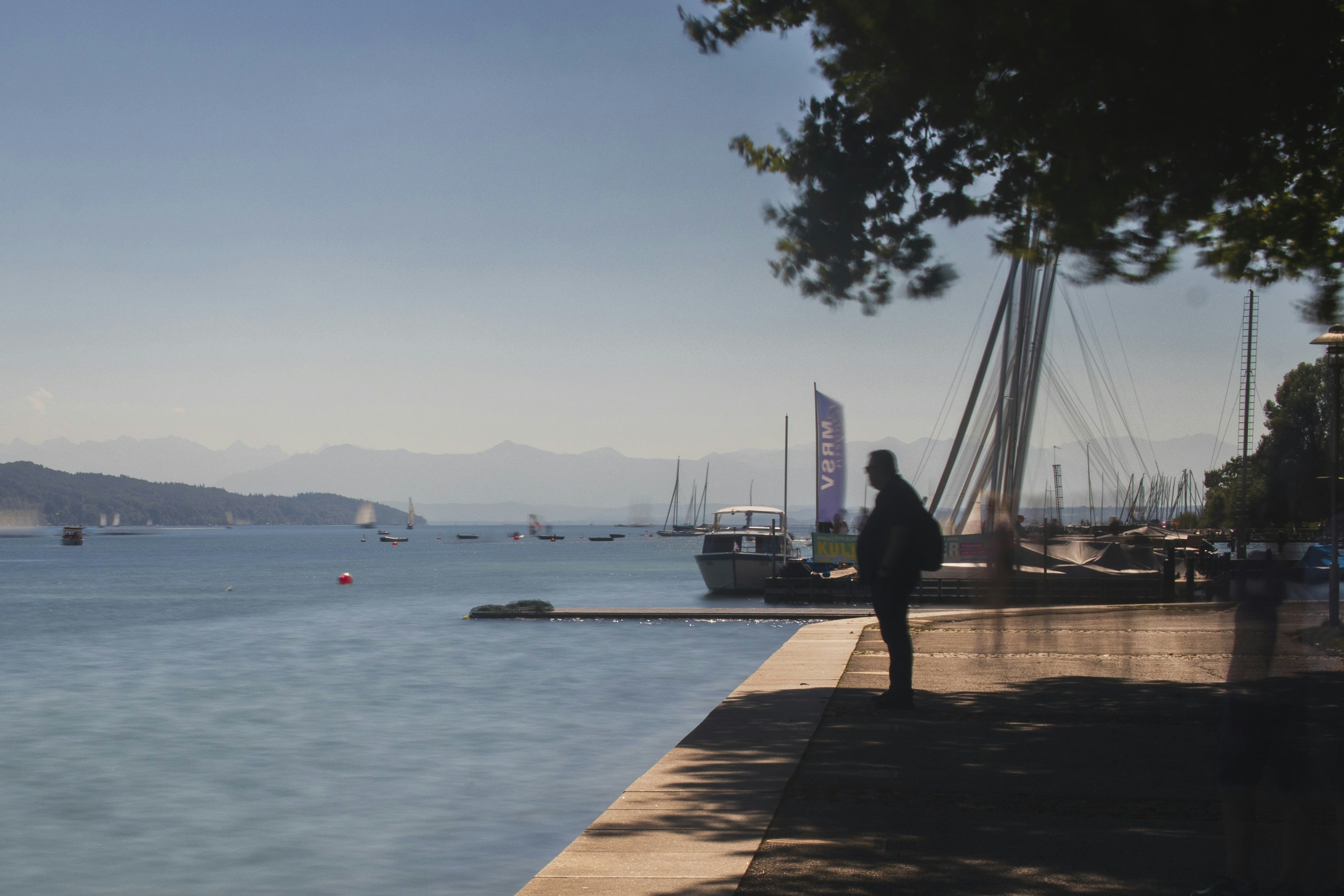 Harbor Silhouette: A Solitary Figure Beside the Distant Sails
