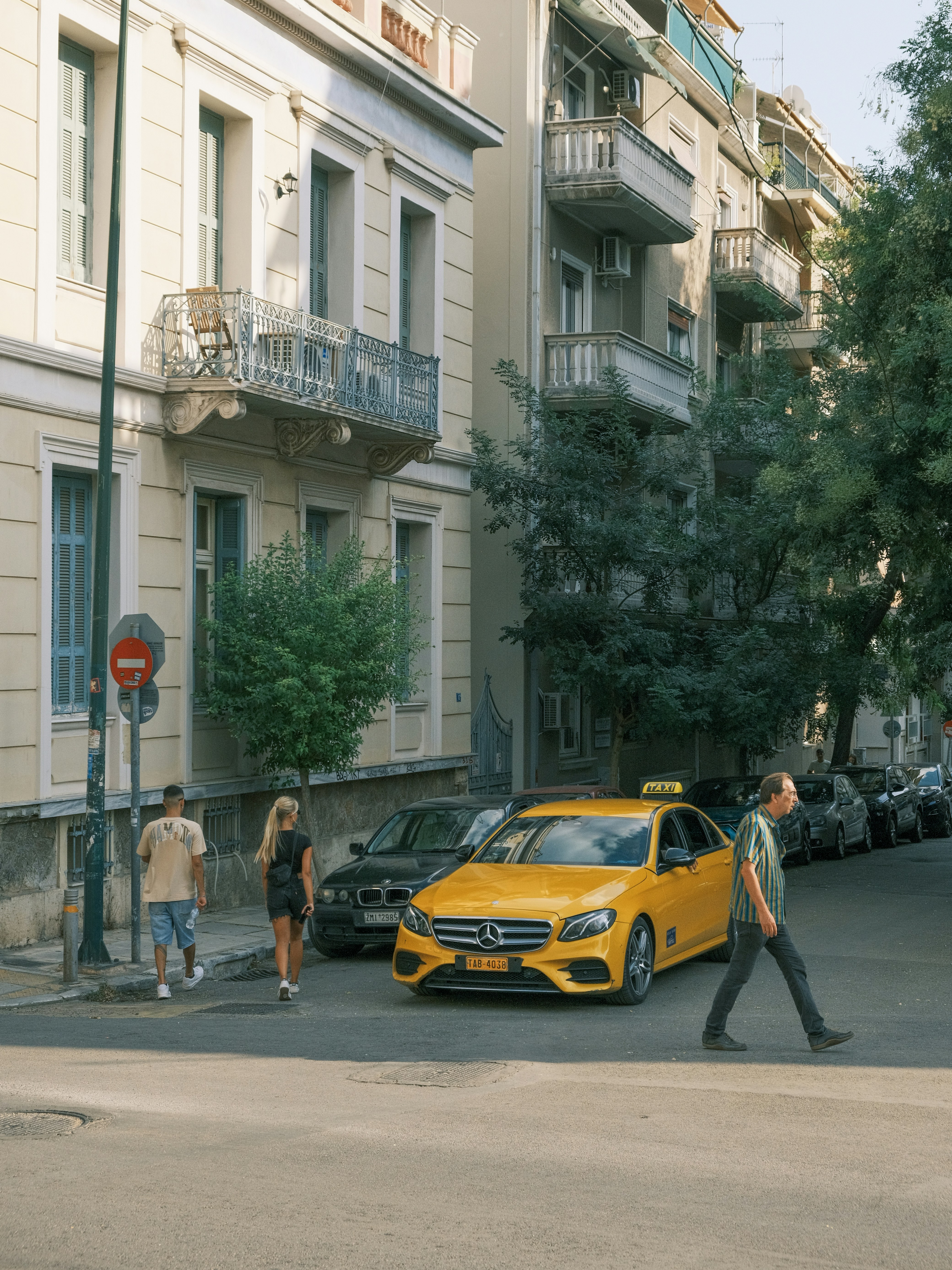 Sunlit Yellow Taxi Pauses Beneath Balconied Facades
