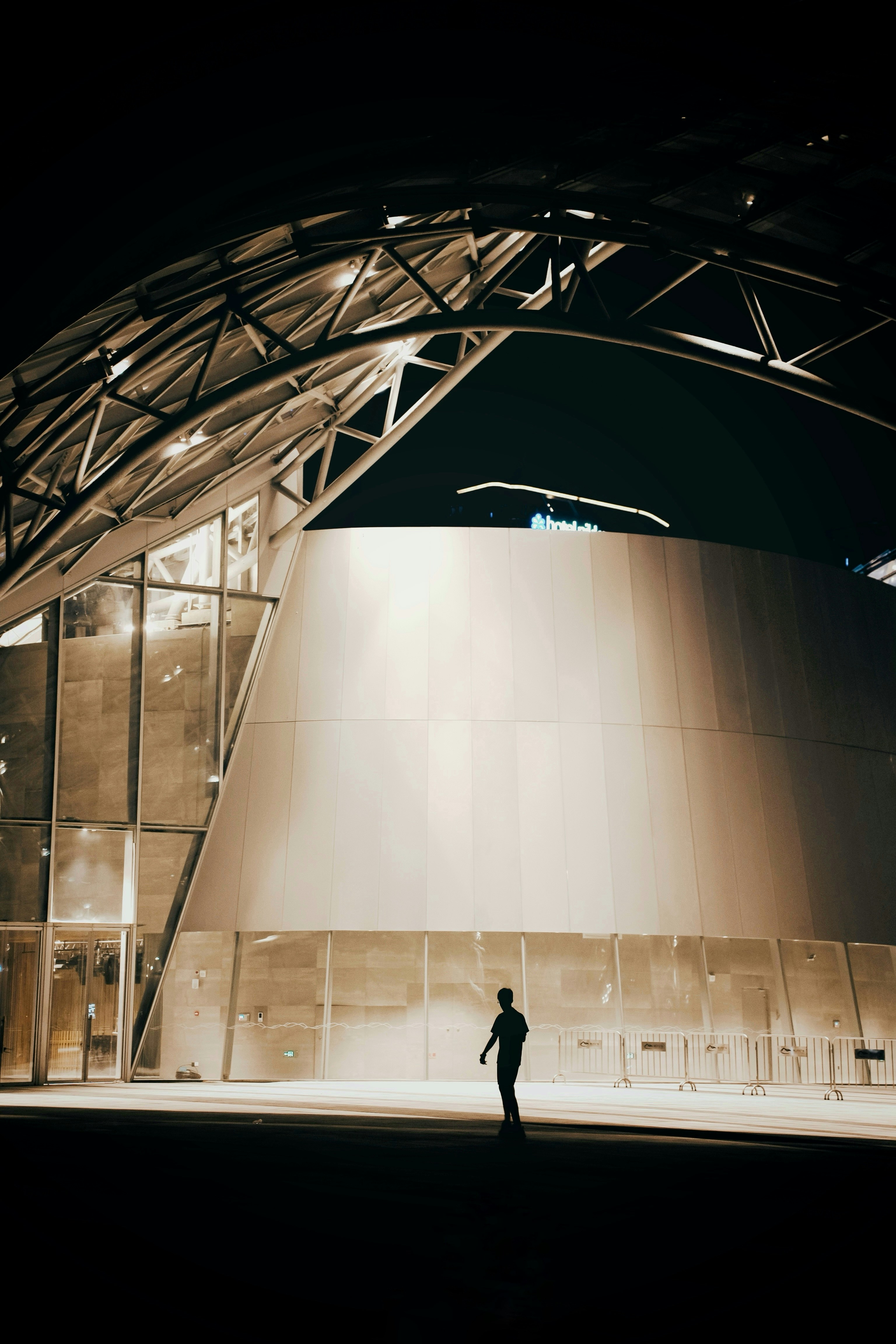 Silhouette in the Arch: Nighttime Walk by the Modern Facade