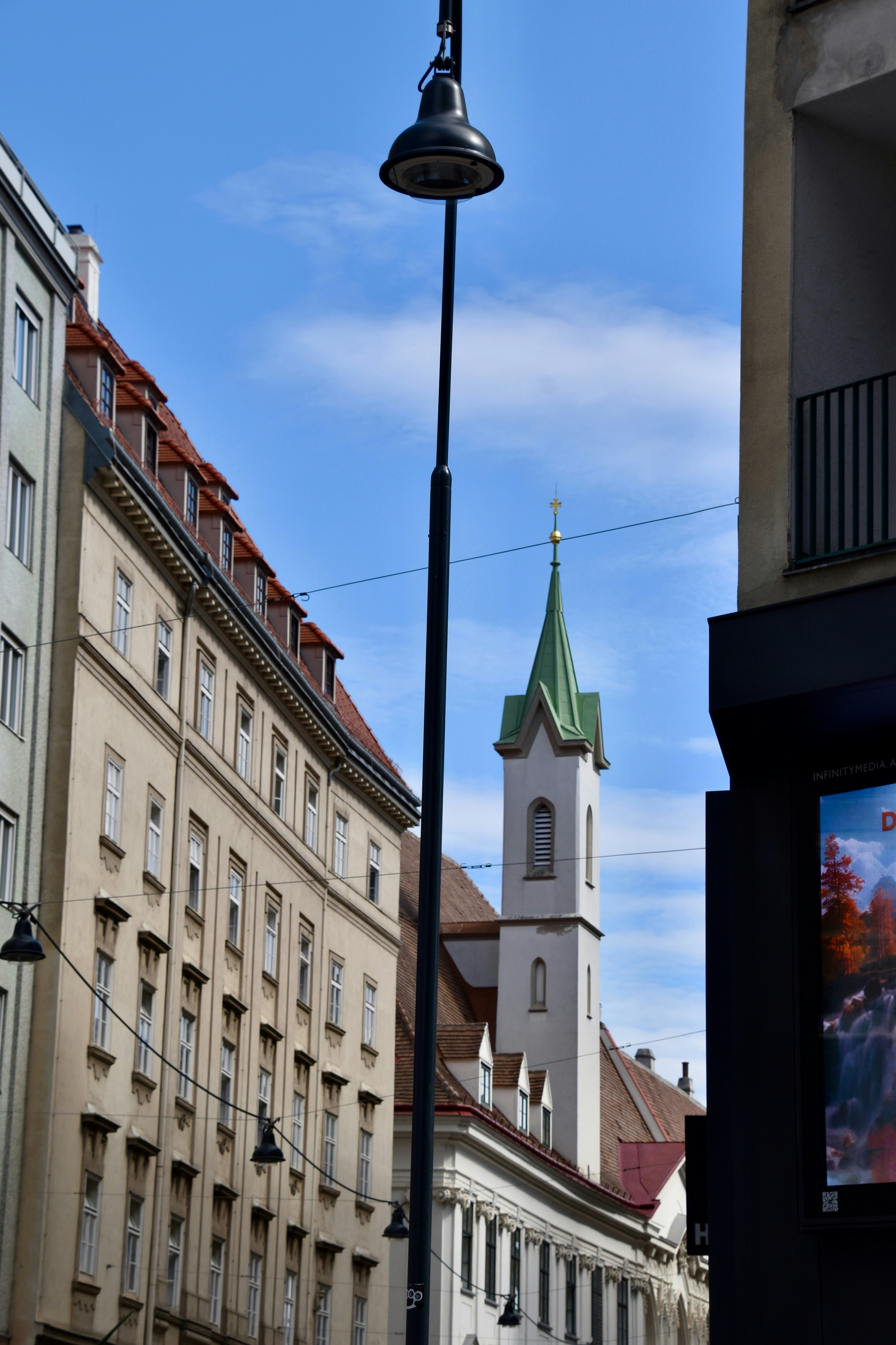 Lamppost at the Crossing: Facades Framing a Green-Steepled Church Under a Blue Sky