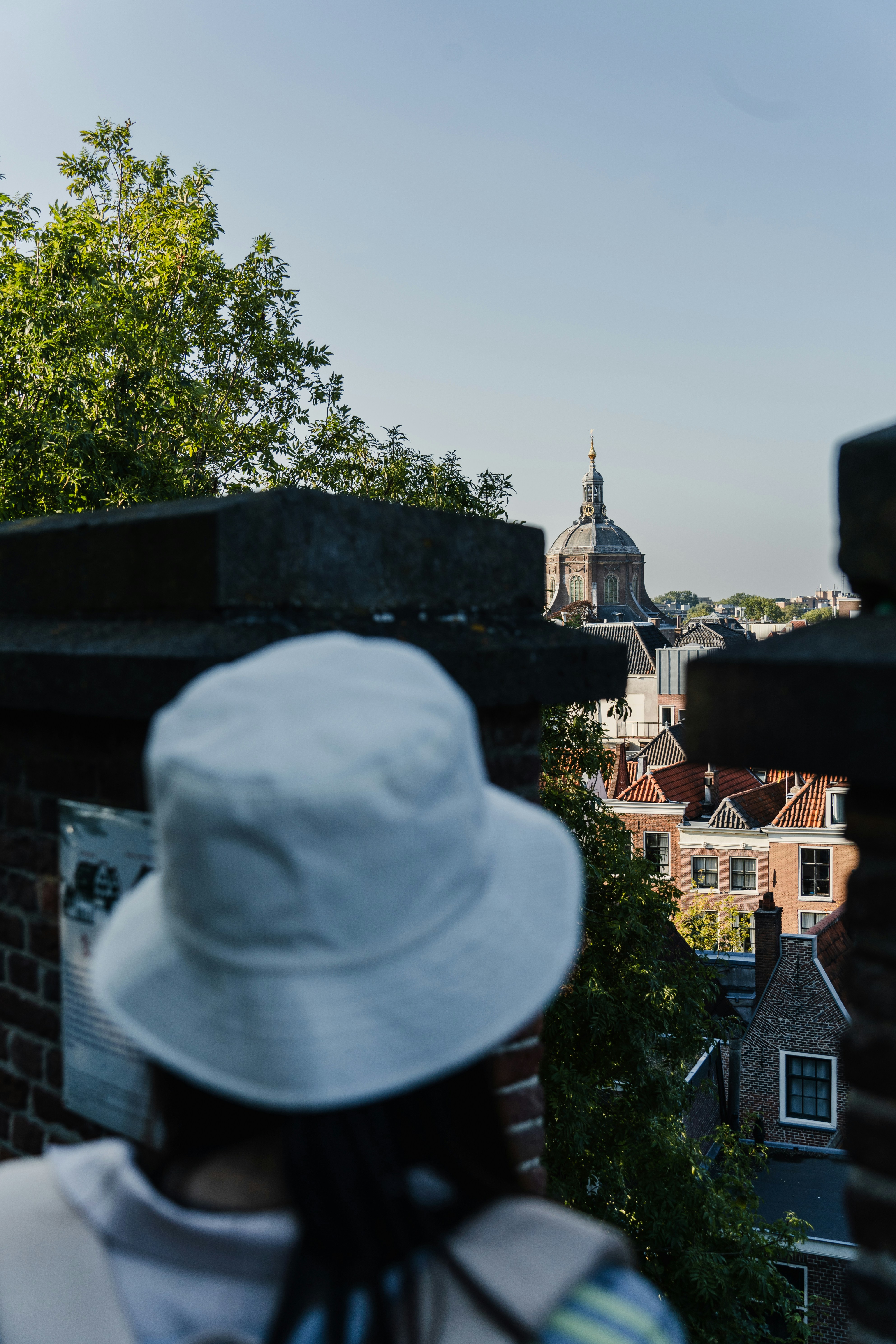 Dome Over the Rooftops: A Quiet Cityscape Framed by a White-Hatted Observer