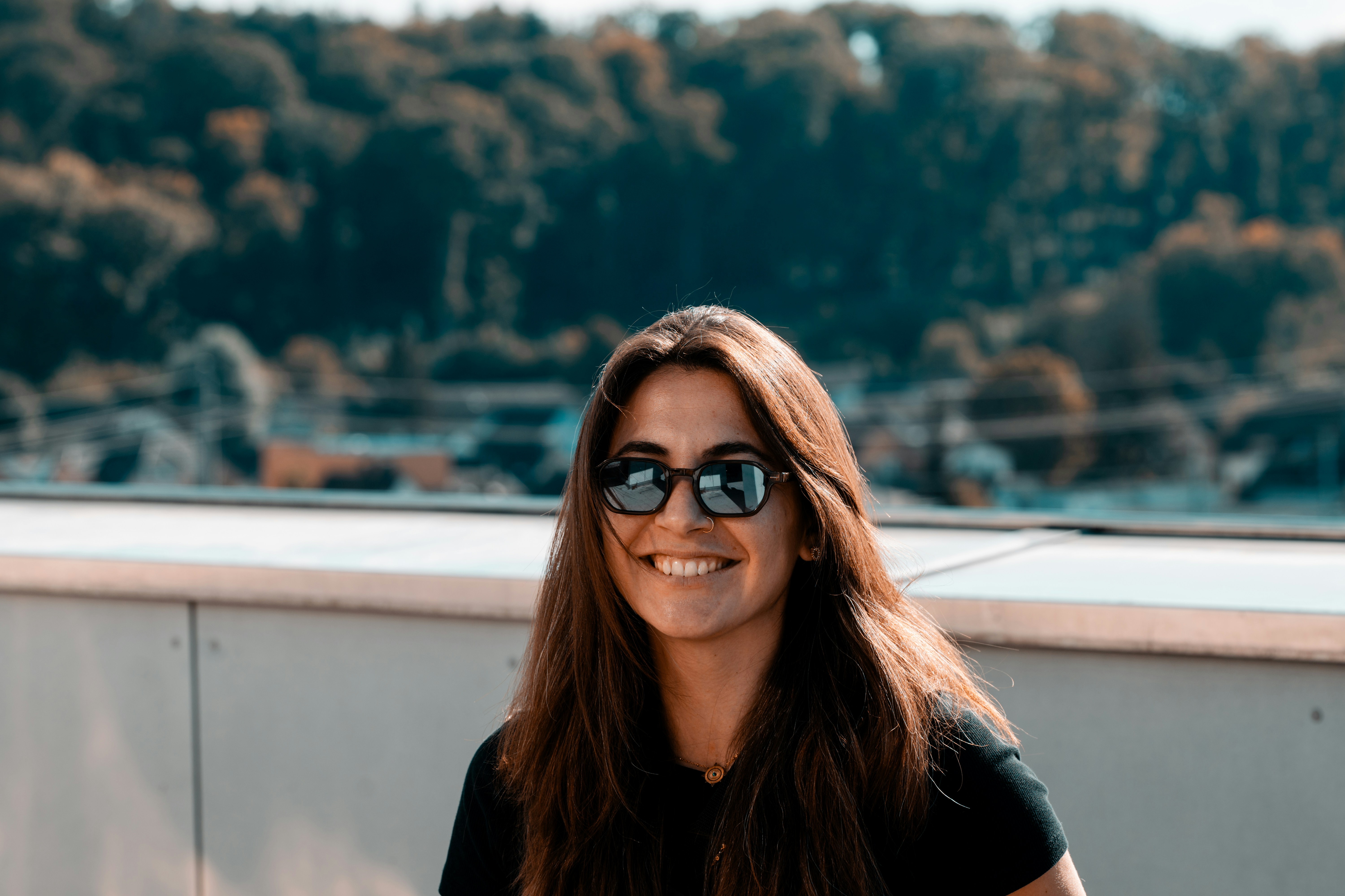A woman wearing sunglasses sitting on a ledge photo – Free Woman Image ...