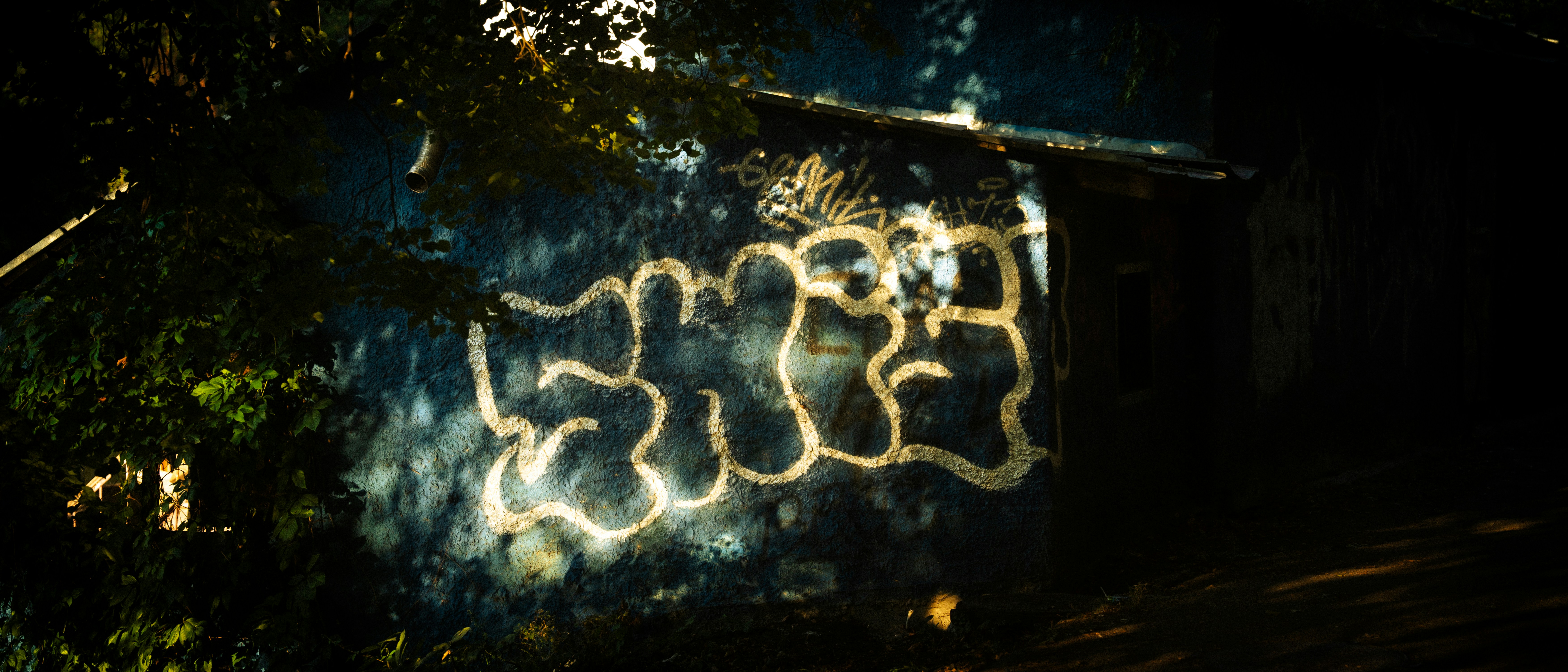 Shaded Blue Wall Graffiti: White Outlines in Quiet Light