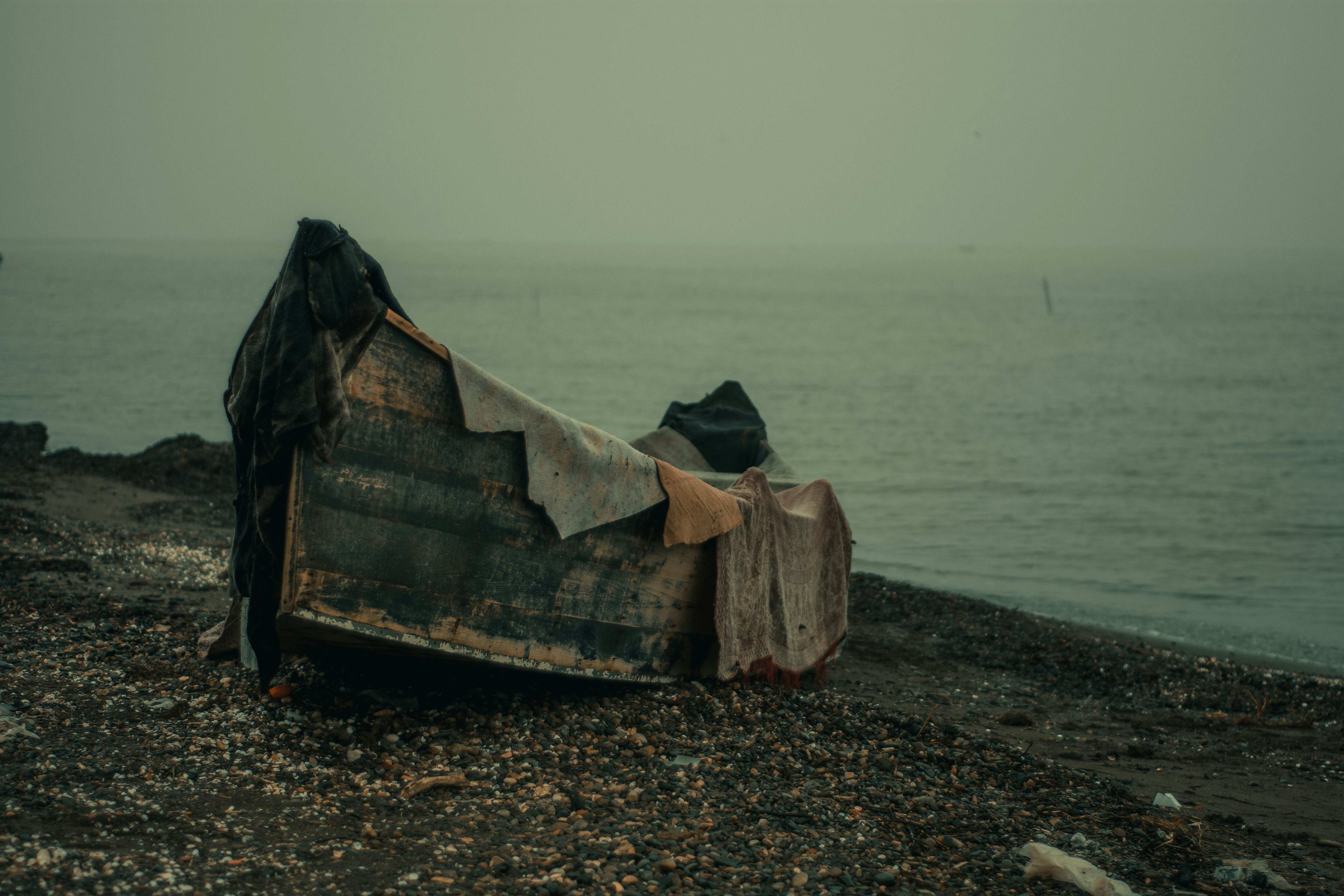 Weathered Boat Resting on a Pebble Shore Under Quiet Dusk