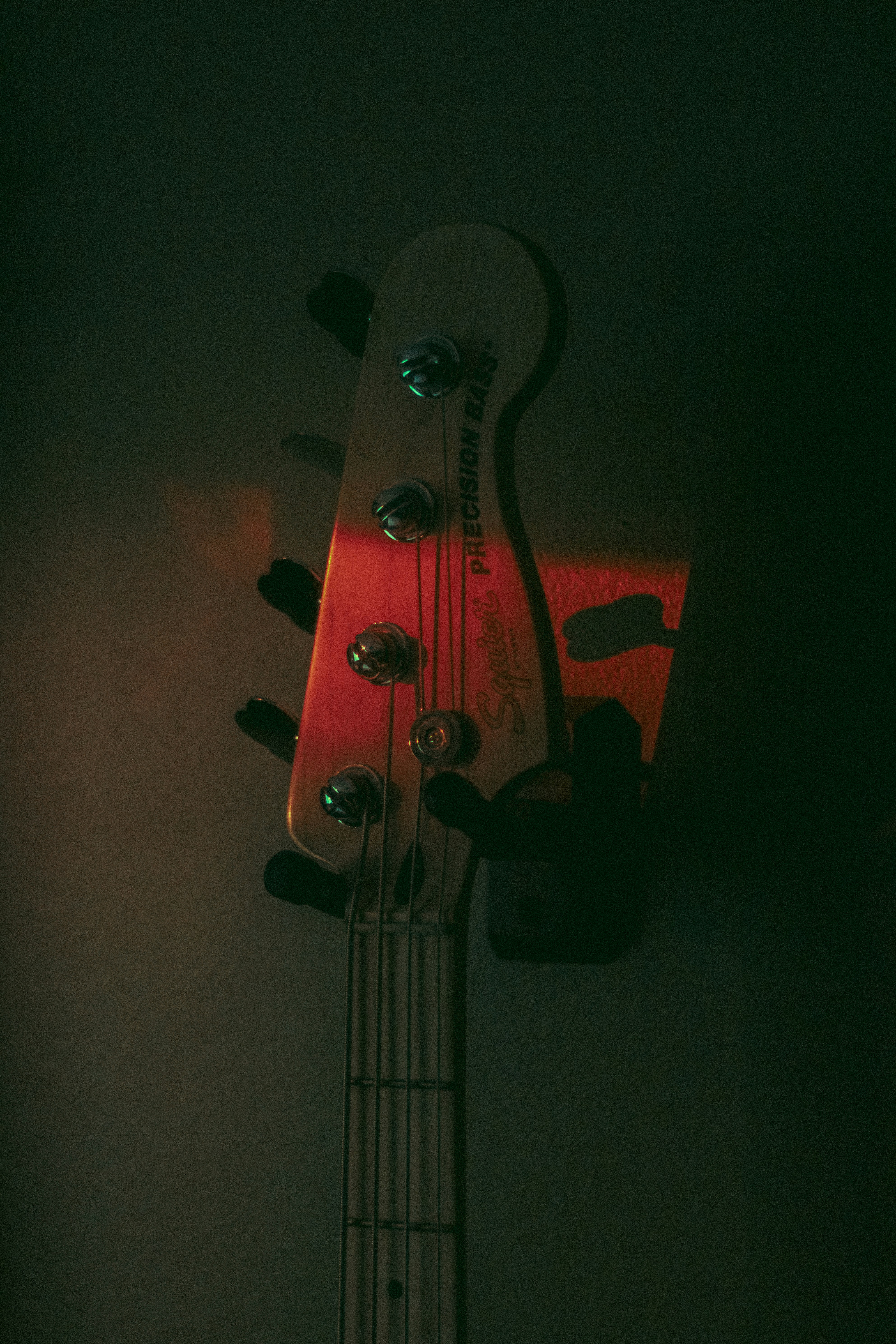 Crimson Glow on a Fender Precision Bass Headstock in a Dim Studio