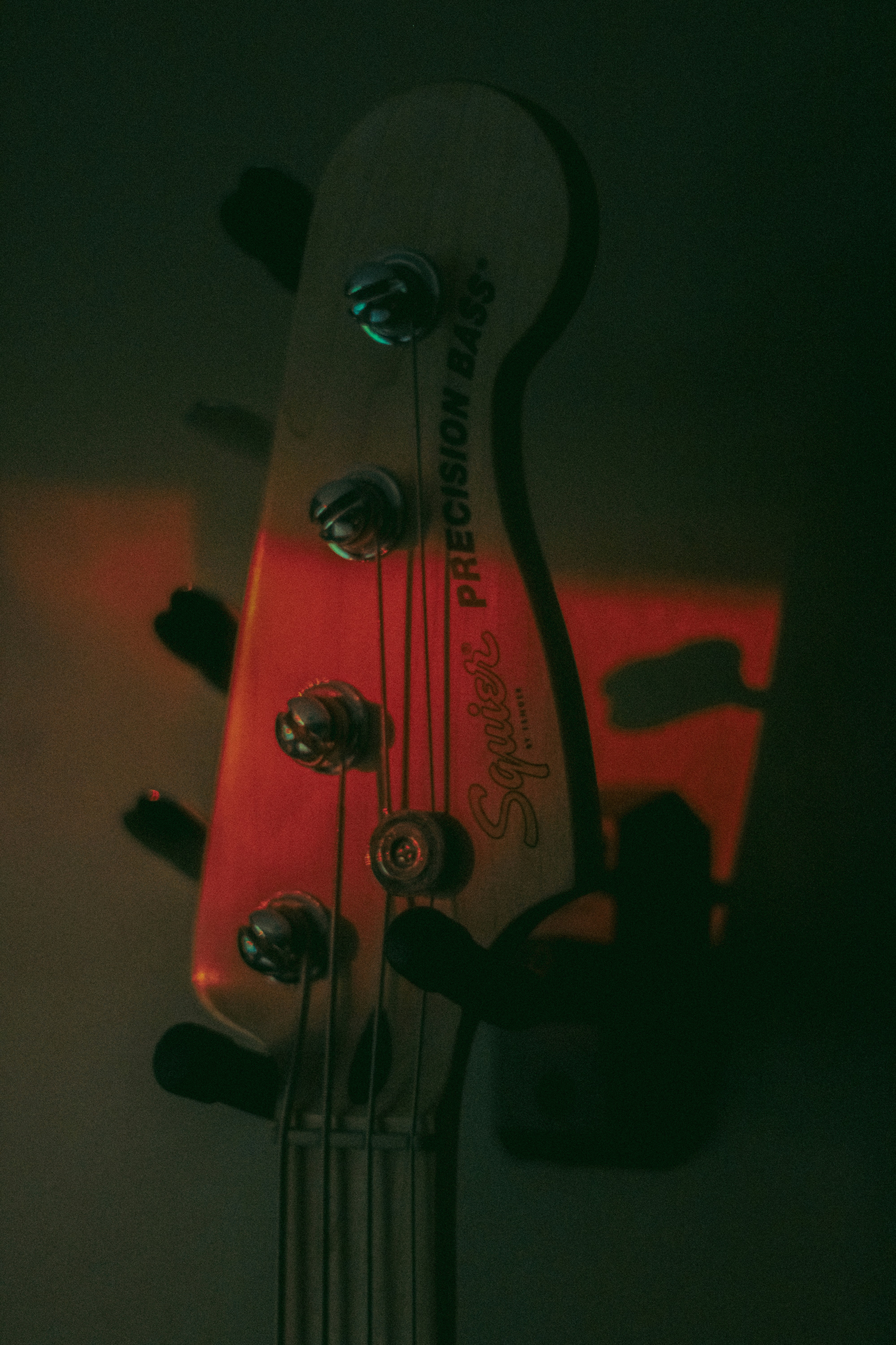 Neon-Shadowed Squier: Precision Bass Headstock in Moody Stage Light