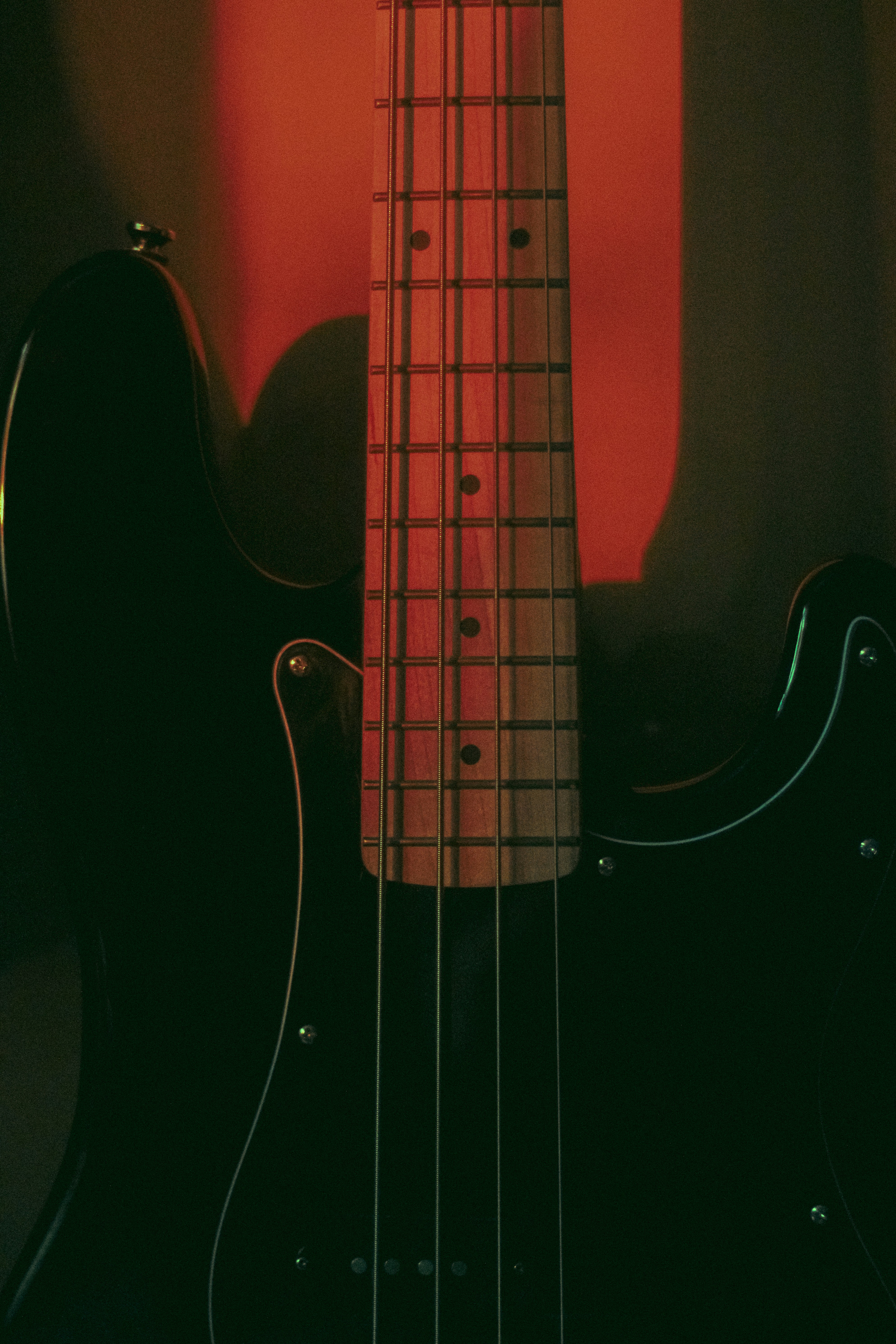 Crimson Necklight: Close-Up of a Black Electric Guitar in Velvet Red