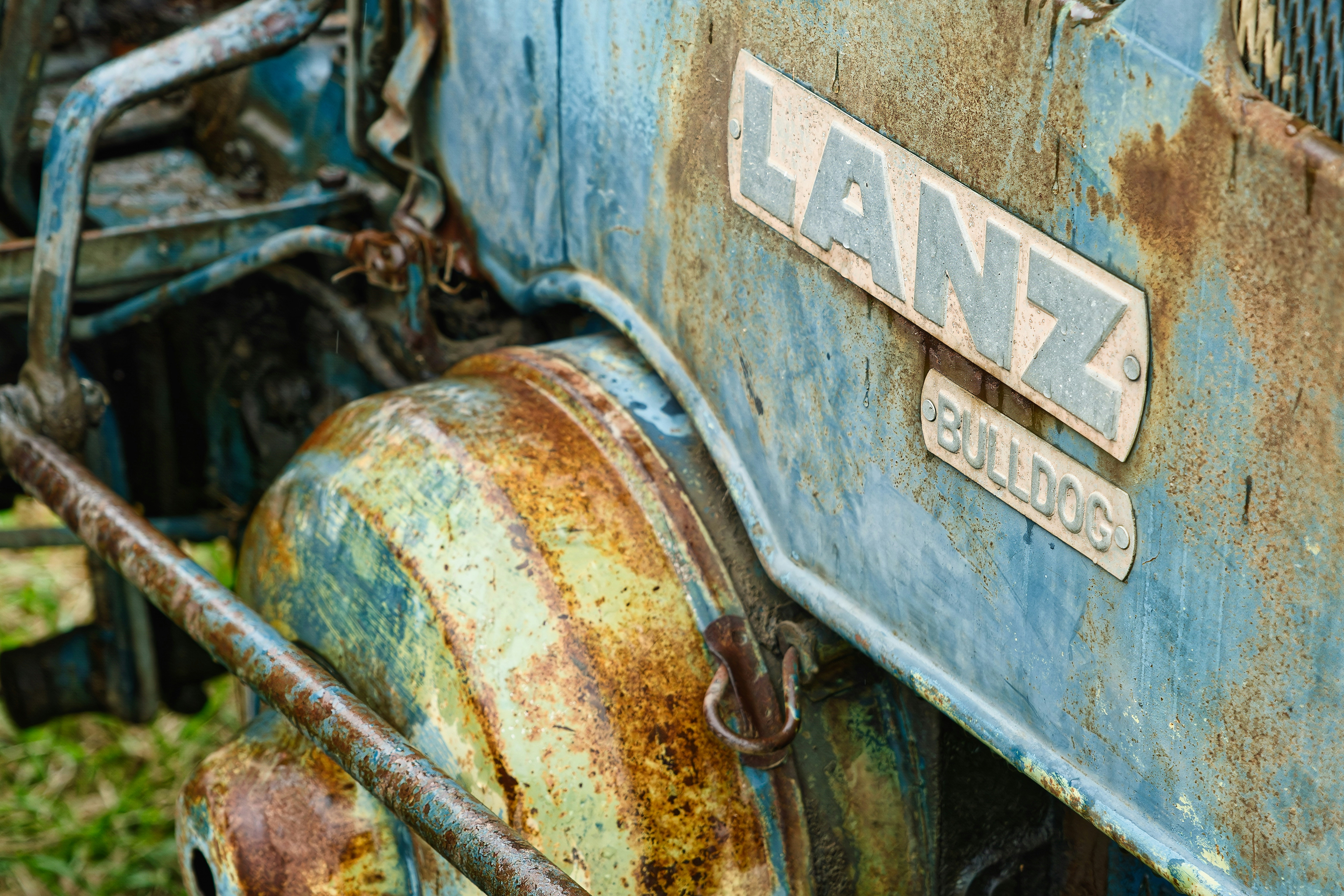 Weathered Power: Close‑up of a rusted Lantz tractor badge on its blue faded body