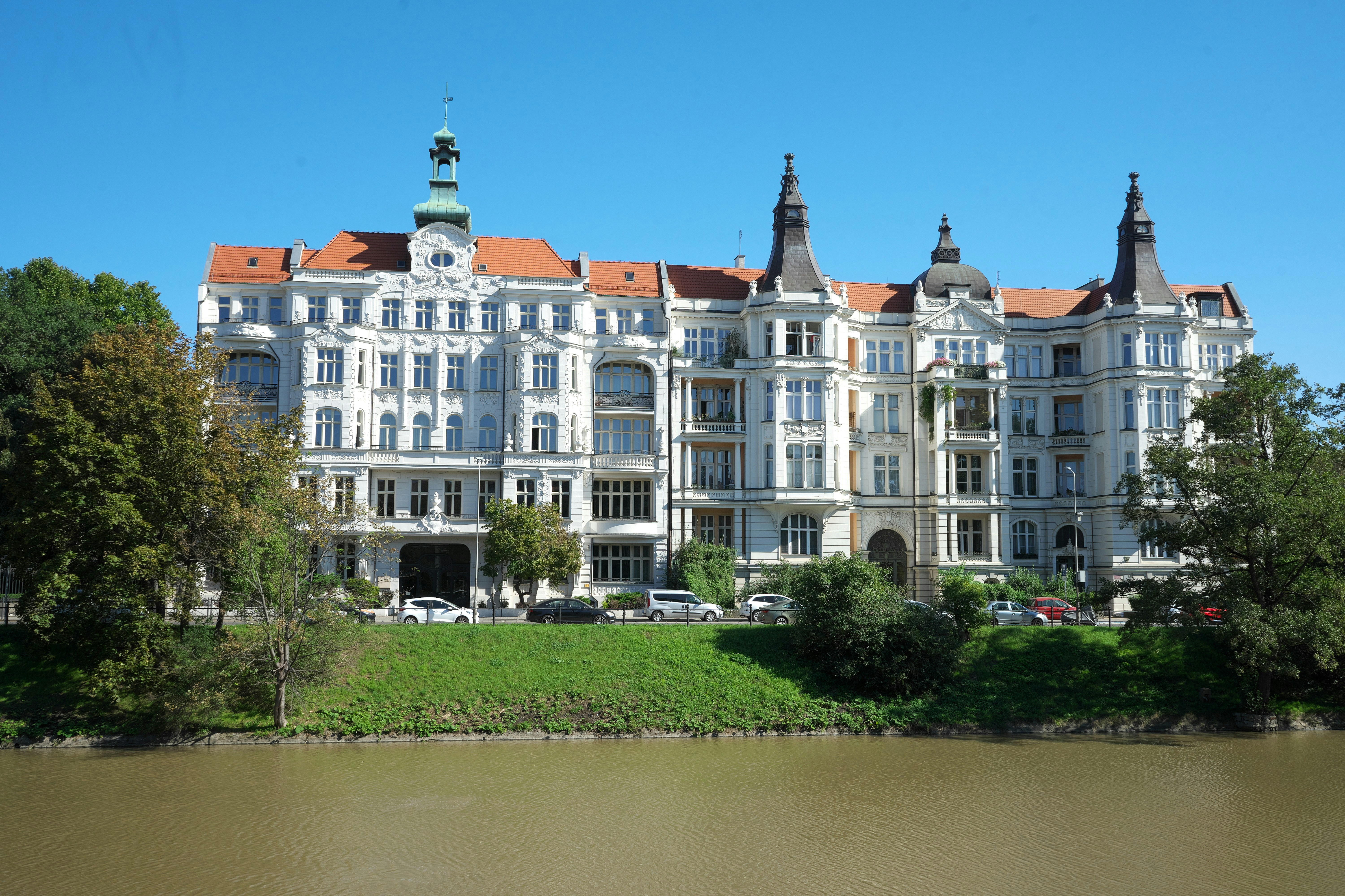 A large white building sitting on the side of a river photo – Free ...