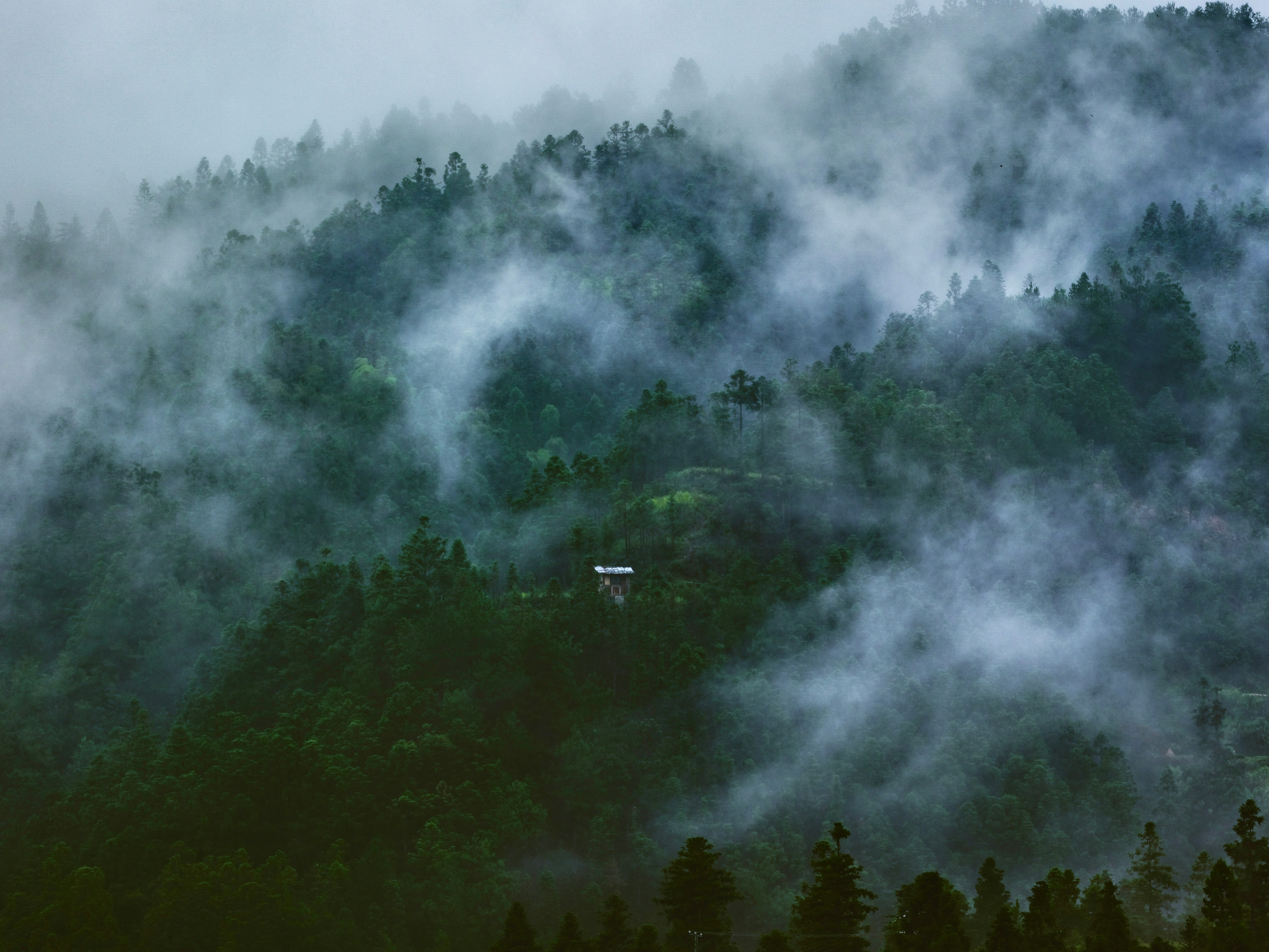 A mountain covered in fog with a house in the distance photo – Free ...