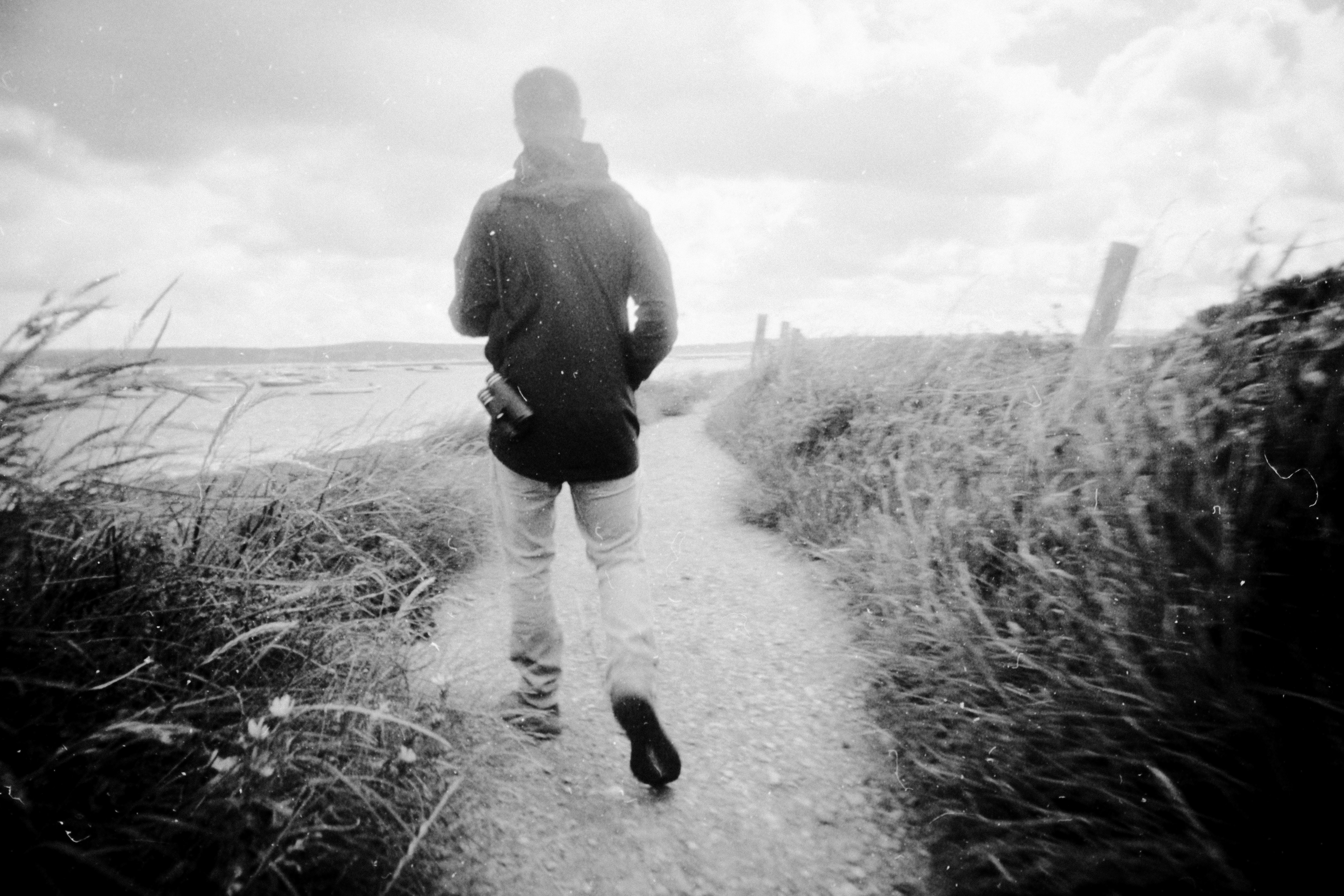 A person walking down a path near the ocean photo – Free Man Image on ...
